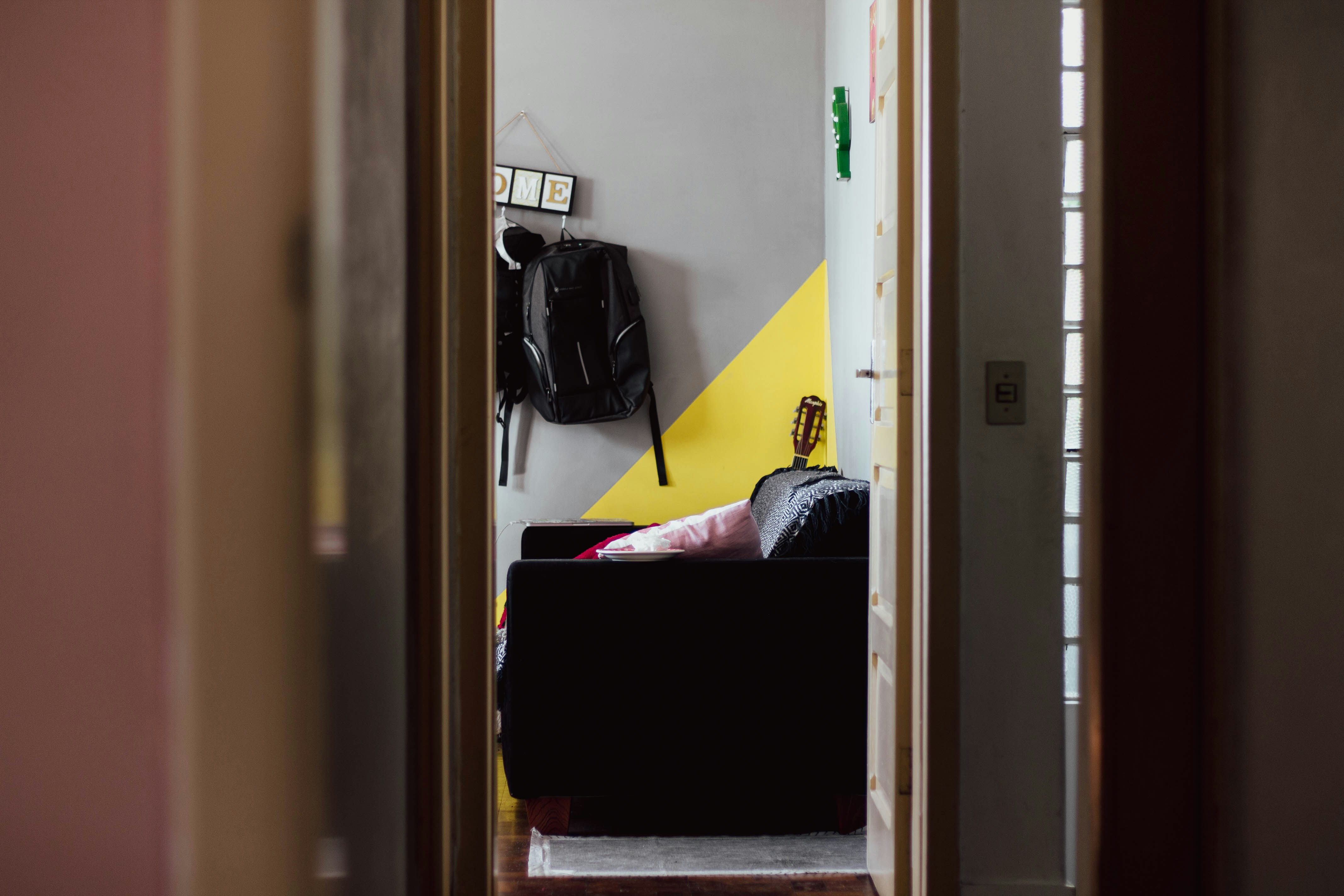 Doorway to Color: A Narrow Hallway Framing a Cozy Living Room with a Yellow Accent