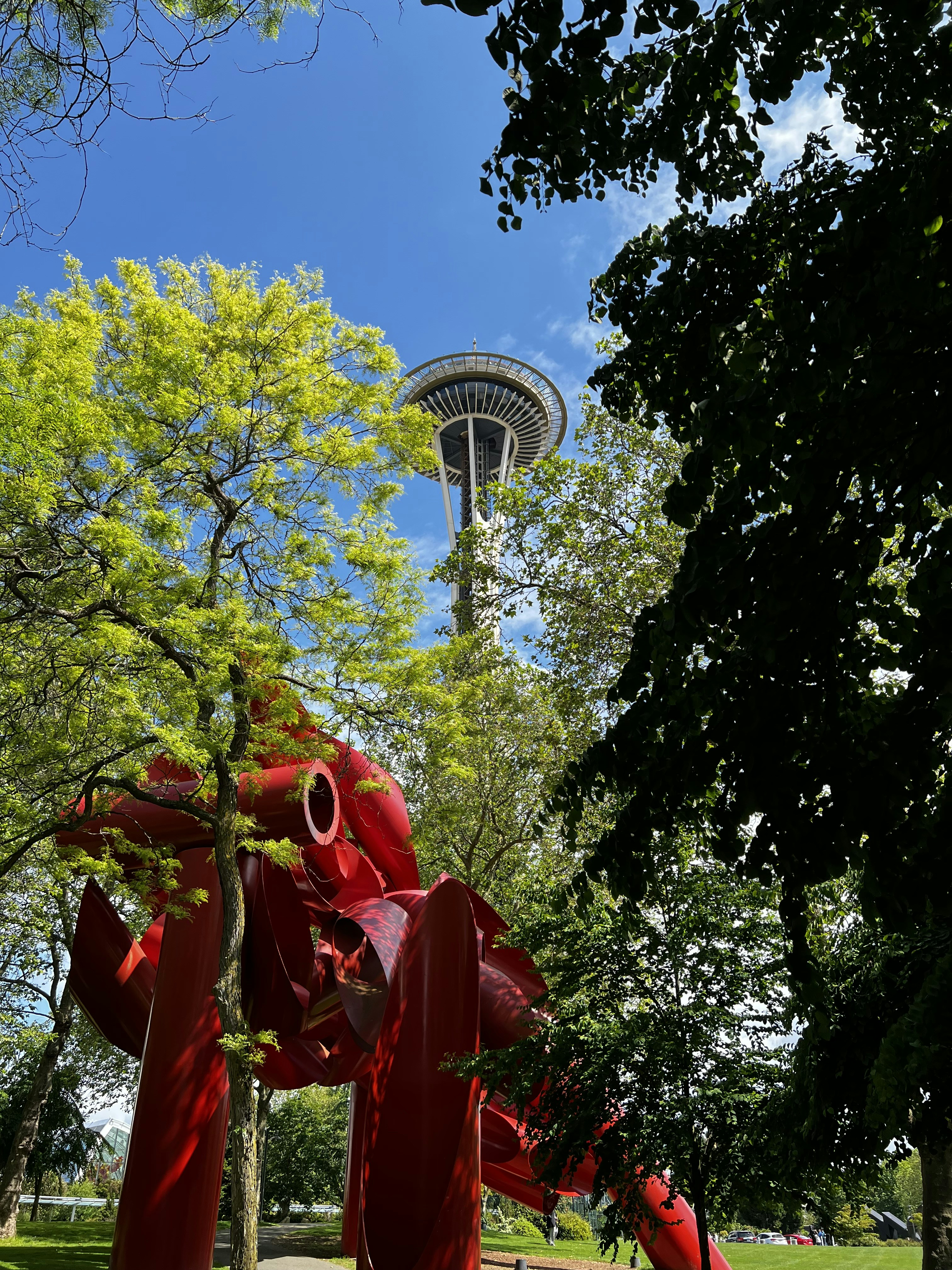 Skyward Red: A Towering Metal Figure Among Canopy