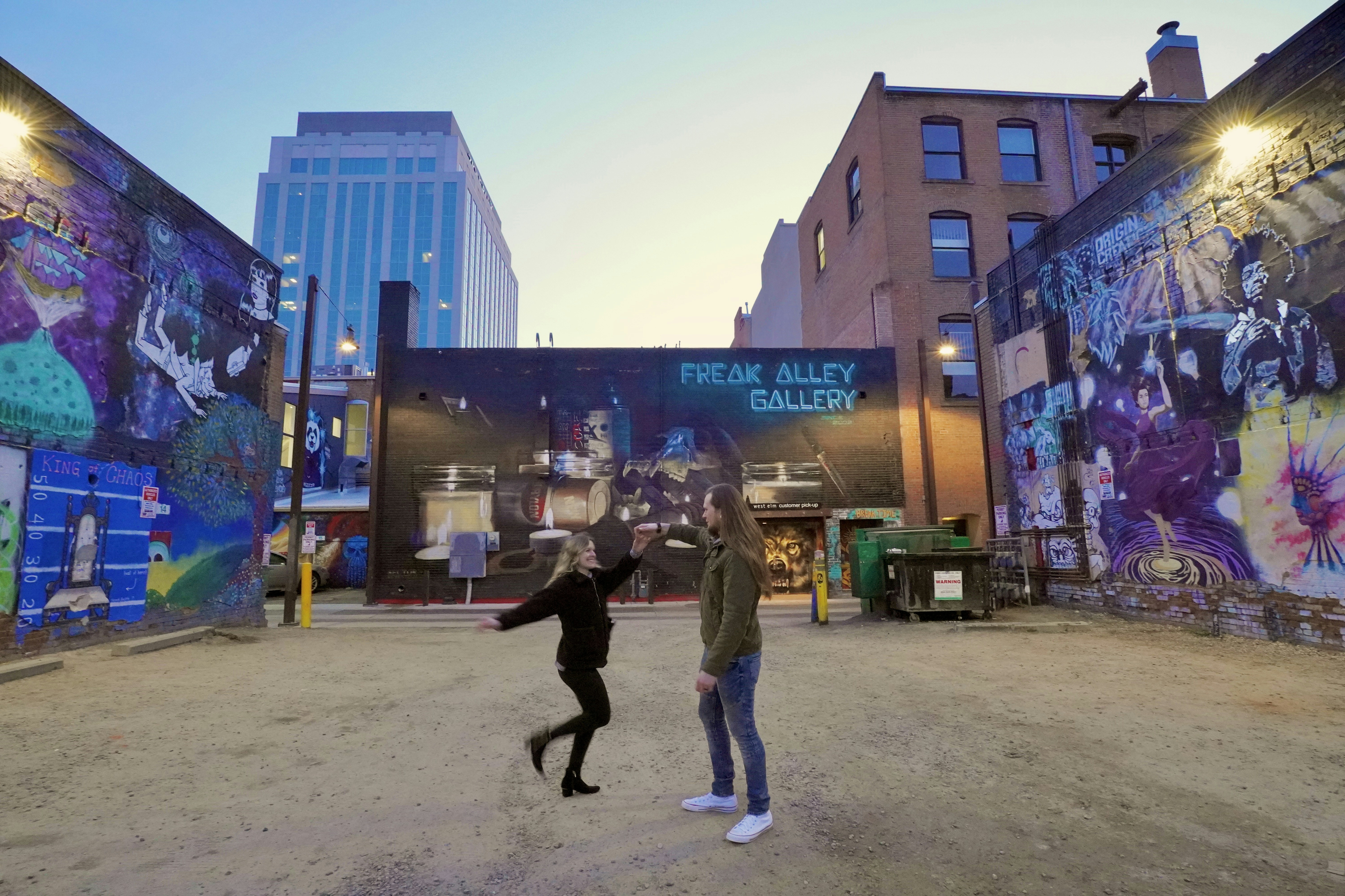 Midnight mural meeting: two figures dance in front of Freak Alley Gallery