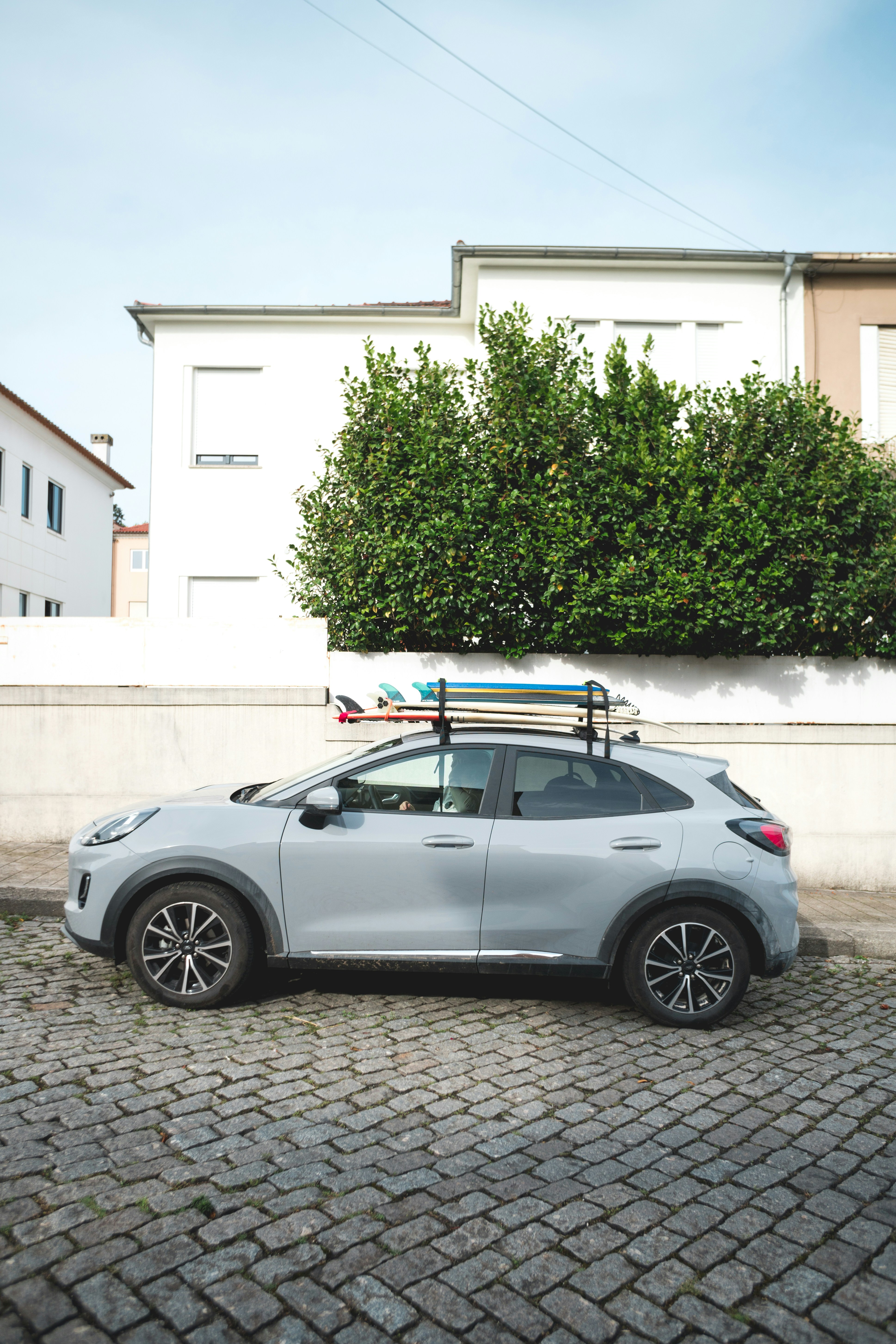 Cobblestone Courtyard Cruiser: Surfboard-Rack SUV on a Quiet Street