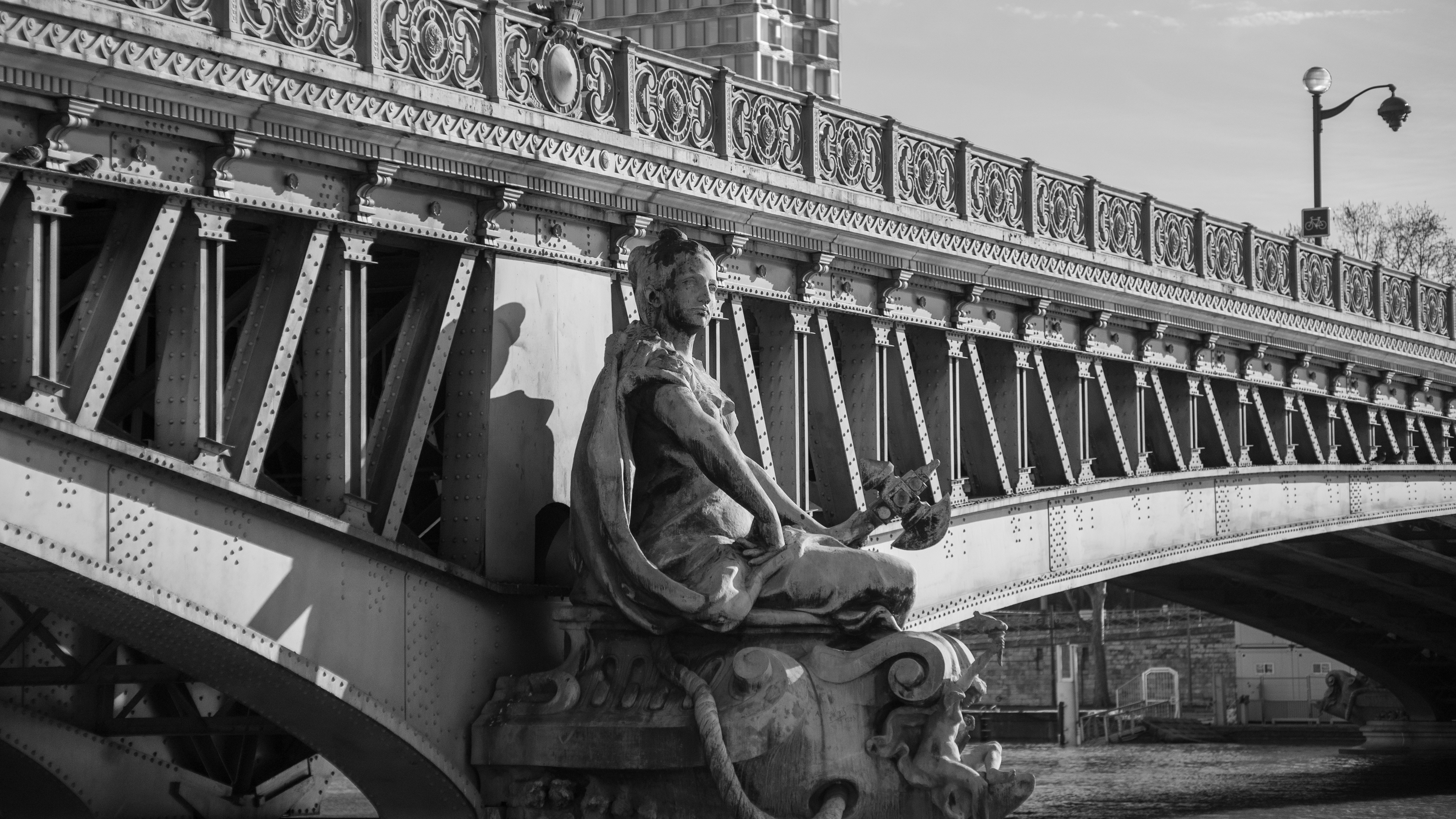 Solitary Figure on a Carved Bridge Beneath Ornate Ironwork