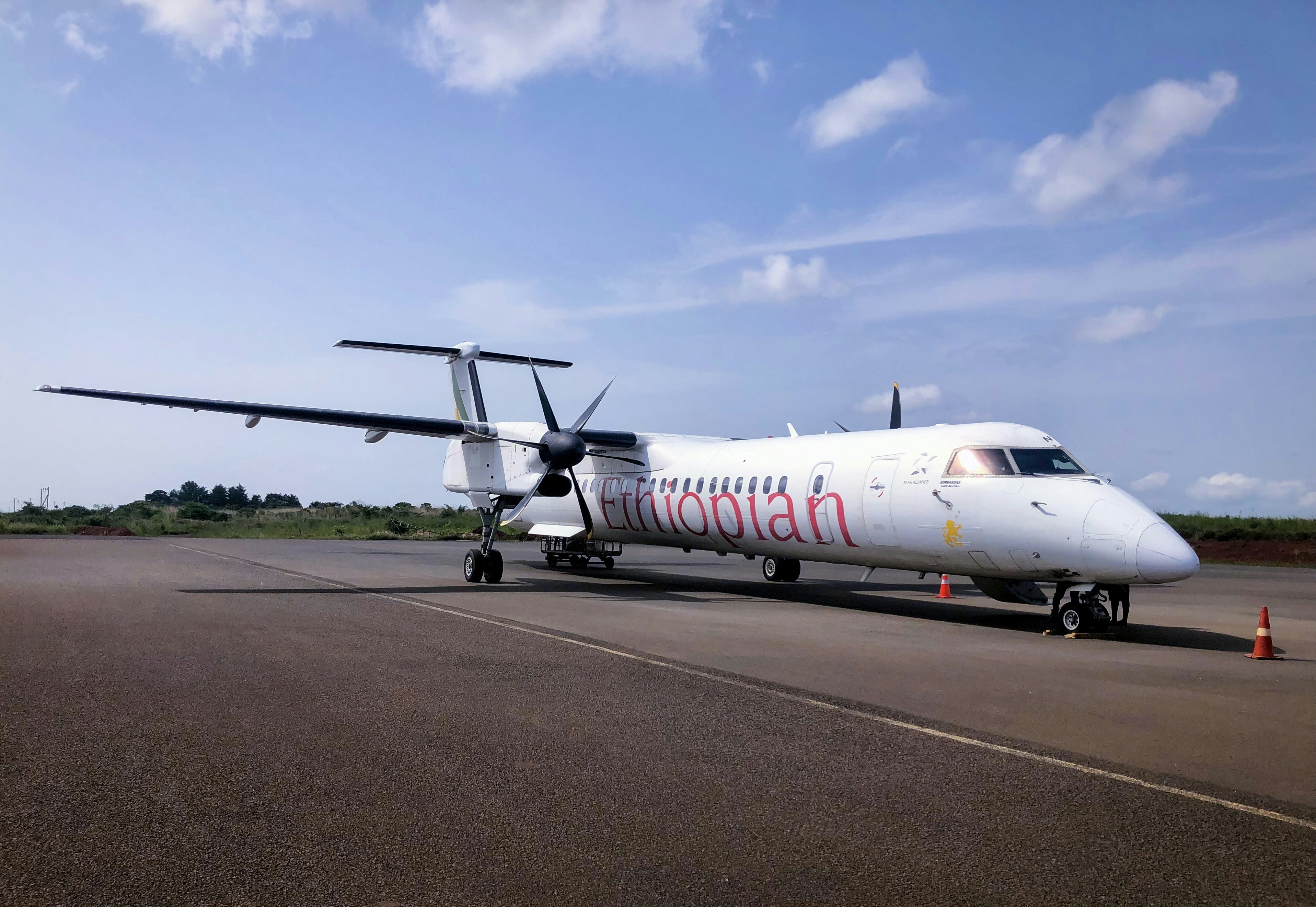 Runway Quiet: A White Jet Paused on a Sunlit Tarmac Under a Wide Blue Sky