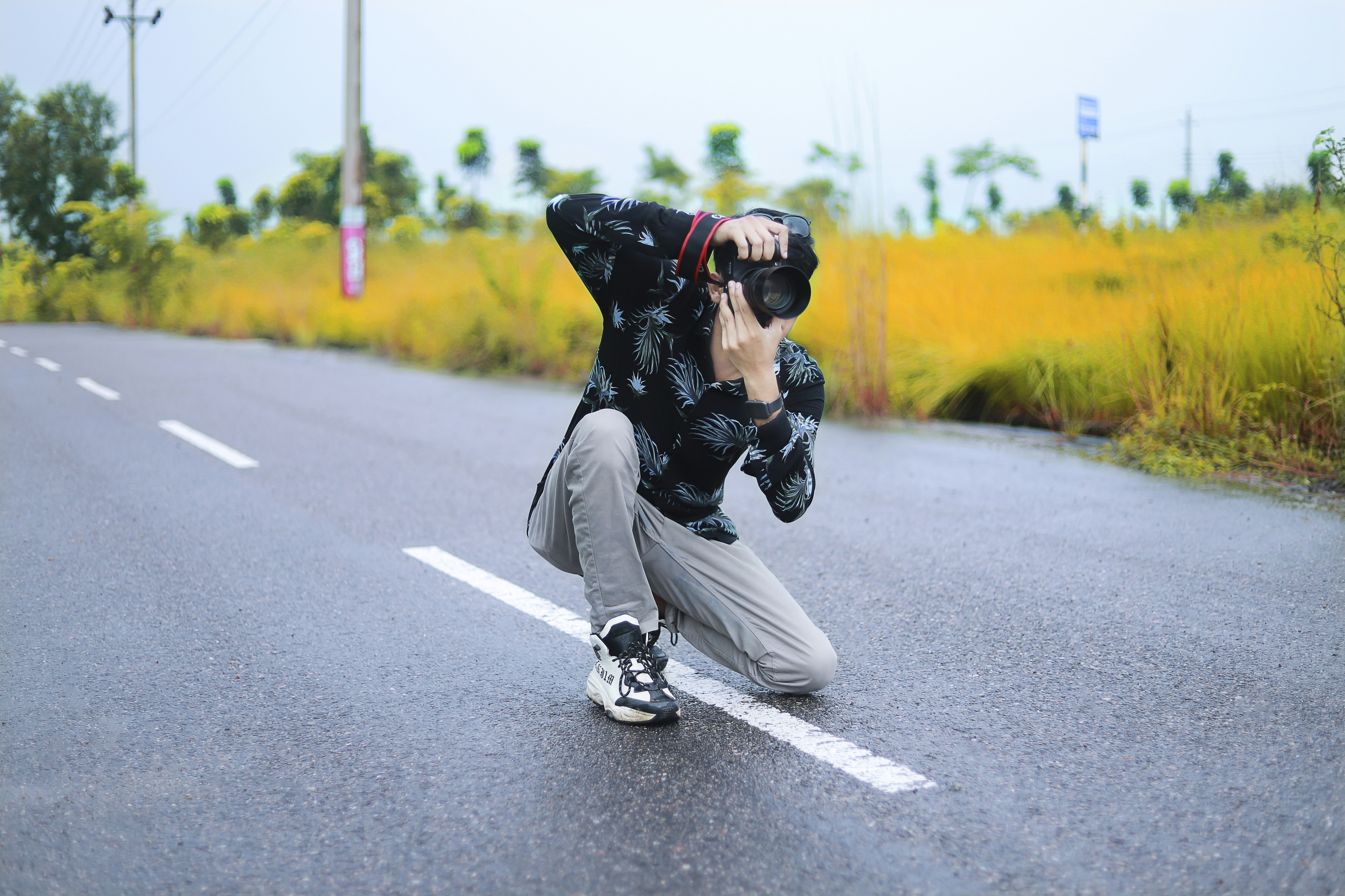 Roadside Studio: Kneeling Photographer Amid a Field of Gold