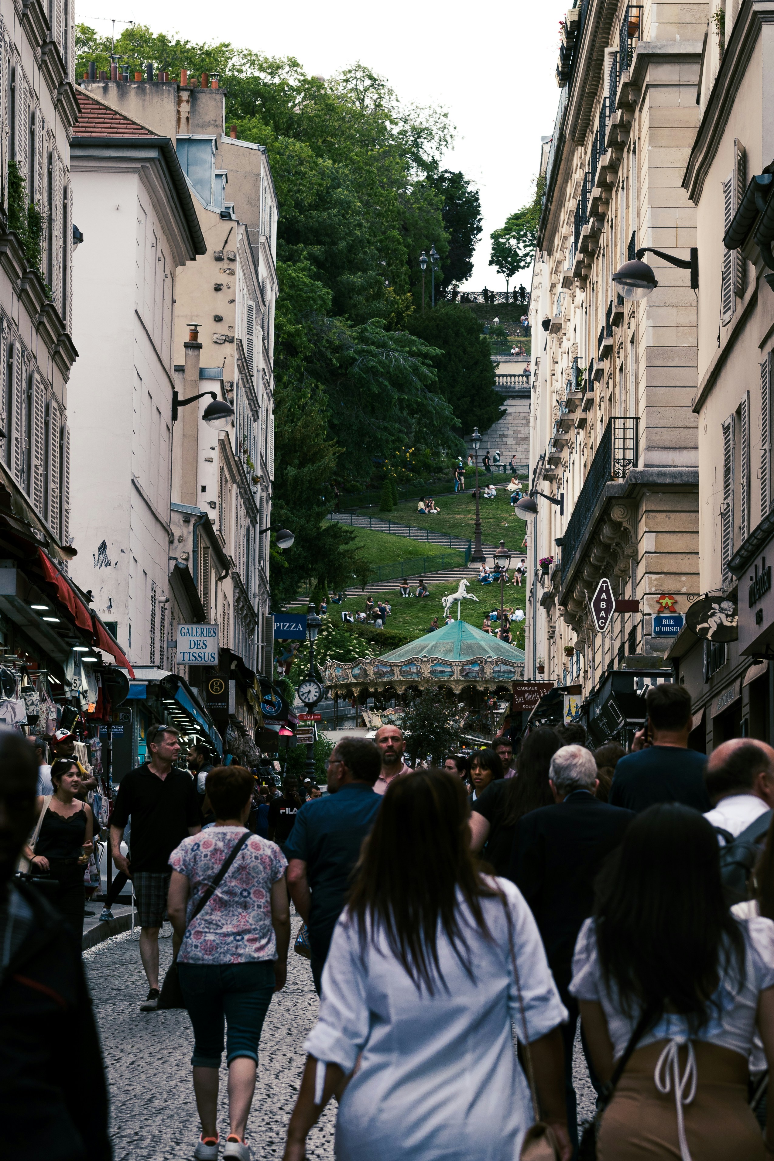 Crowded Street Pulse Toward a Turquoise Canopy Framing a Green Hill