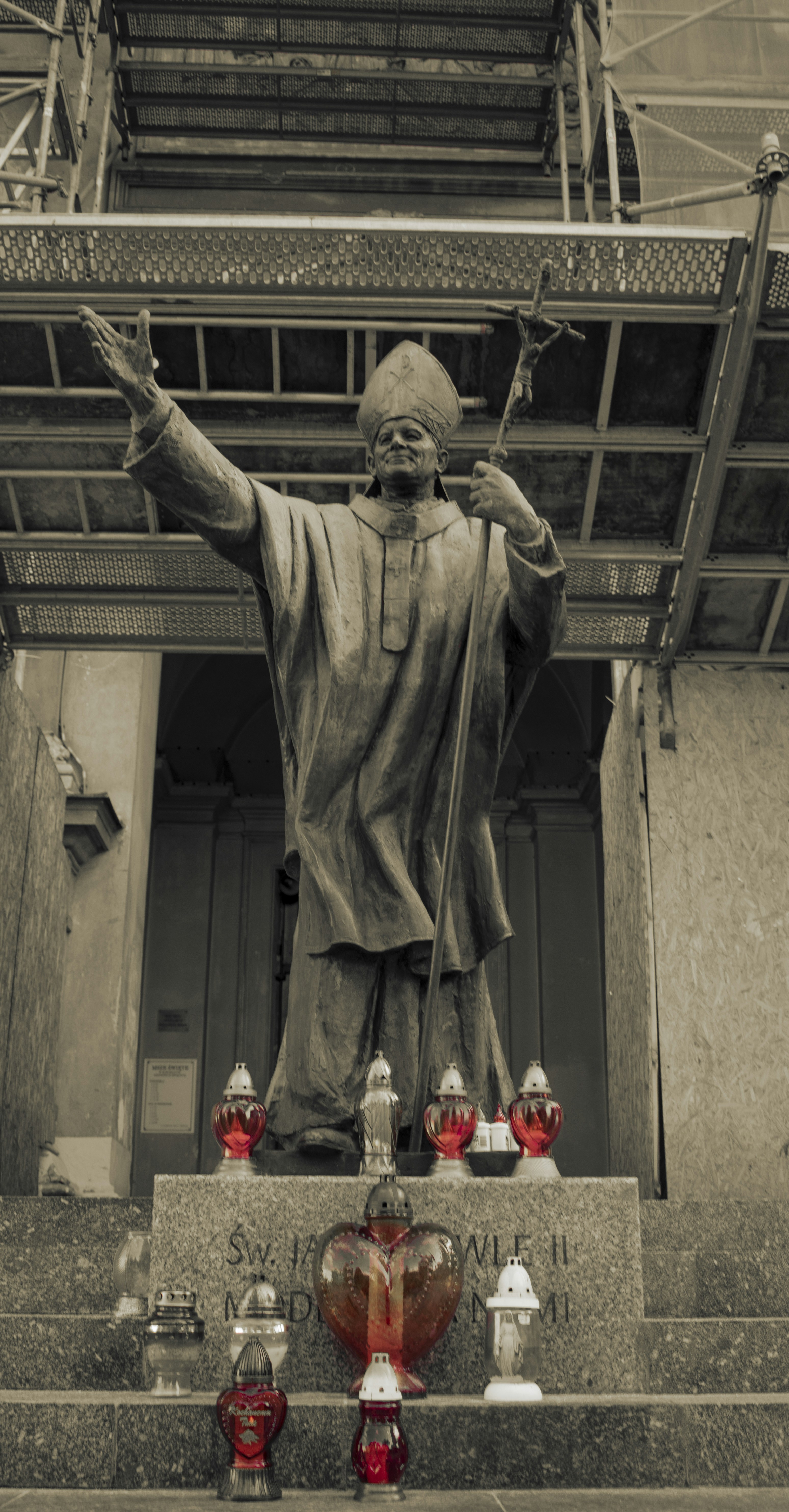 Sepia Sentinel: A Bishop Statue Under Industrial Light