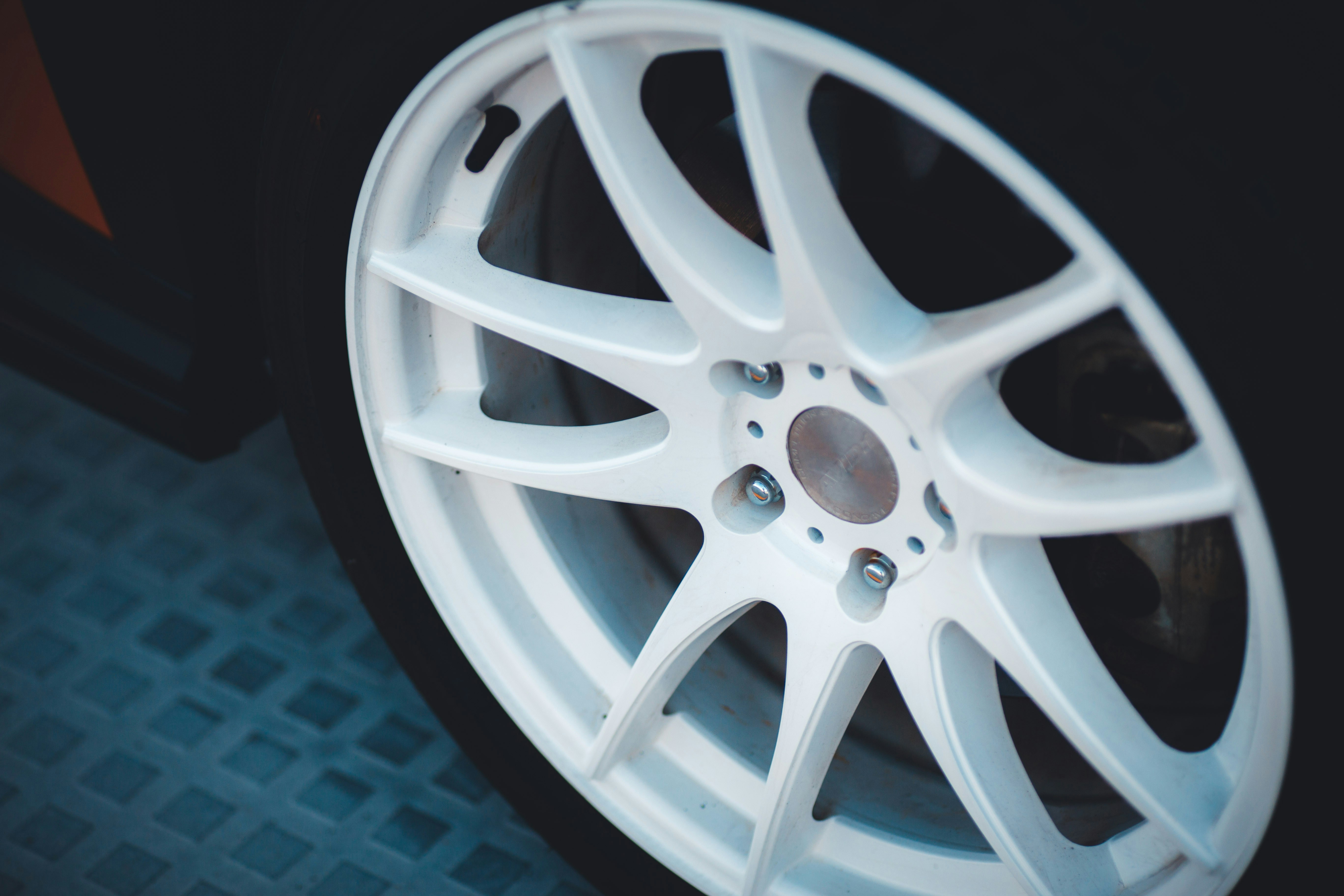 Spoked Geometry: White Alloy Wheel on a Blue Mosaic Floor