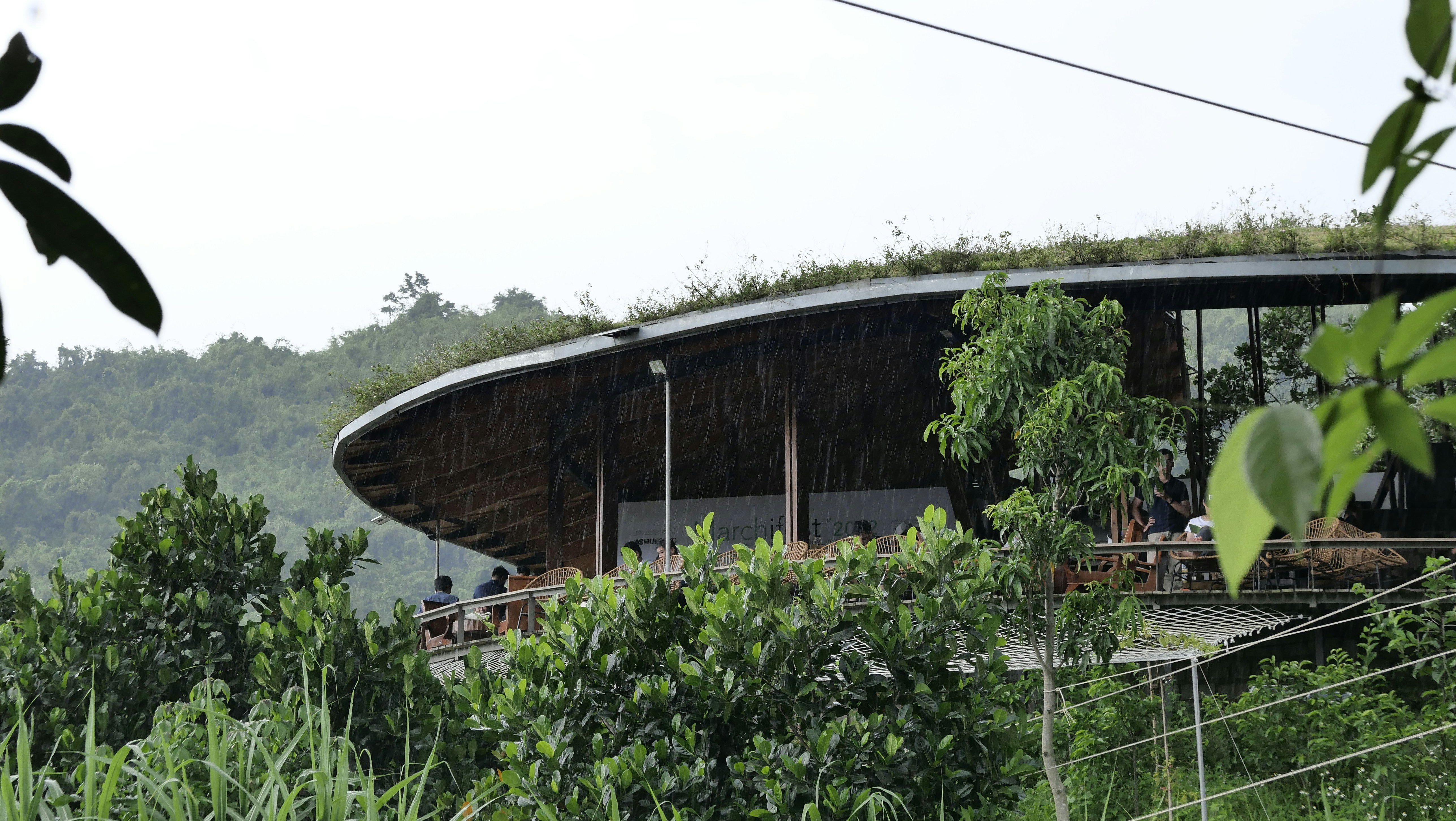 Modern architectural structure nestled among lush greenery, showcasing eco-friendly design principles. Rain enhances the serene atmosphere.