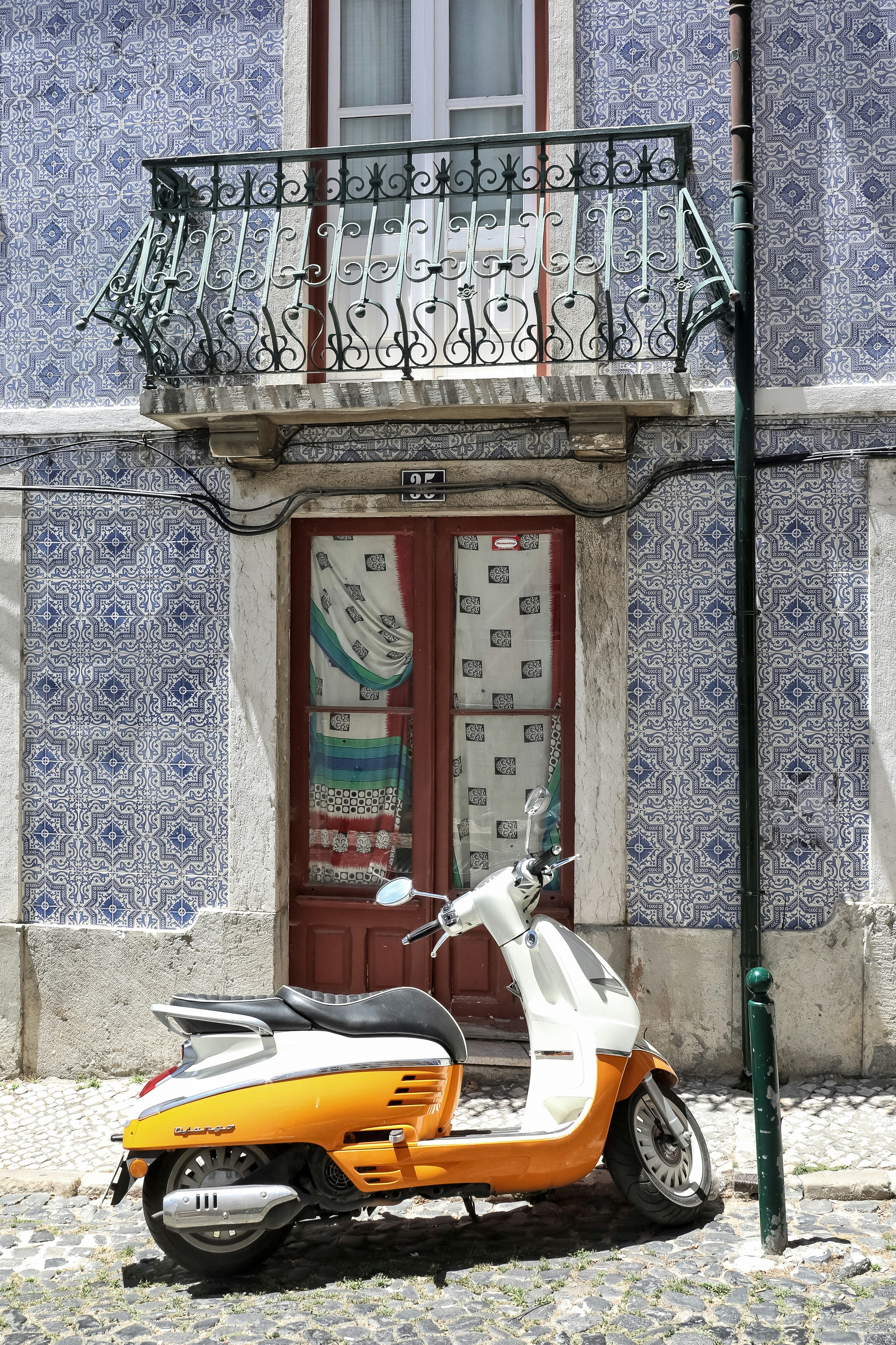 Vespa Against a Patterned Azulejo Wall on a Sunlit Lisbon Street