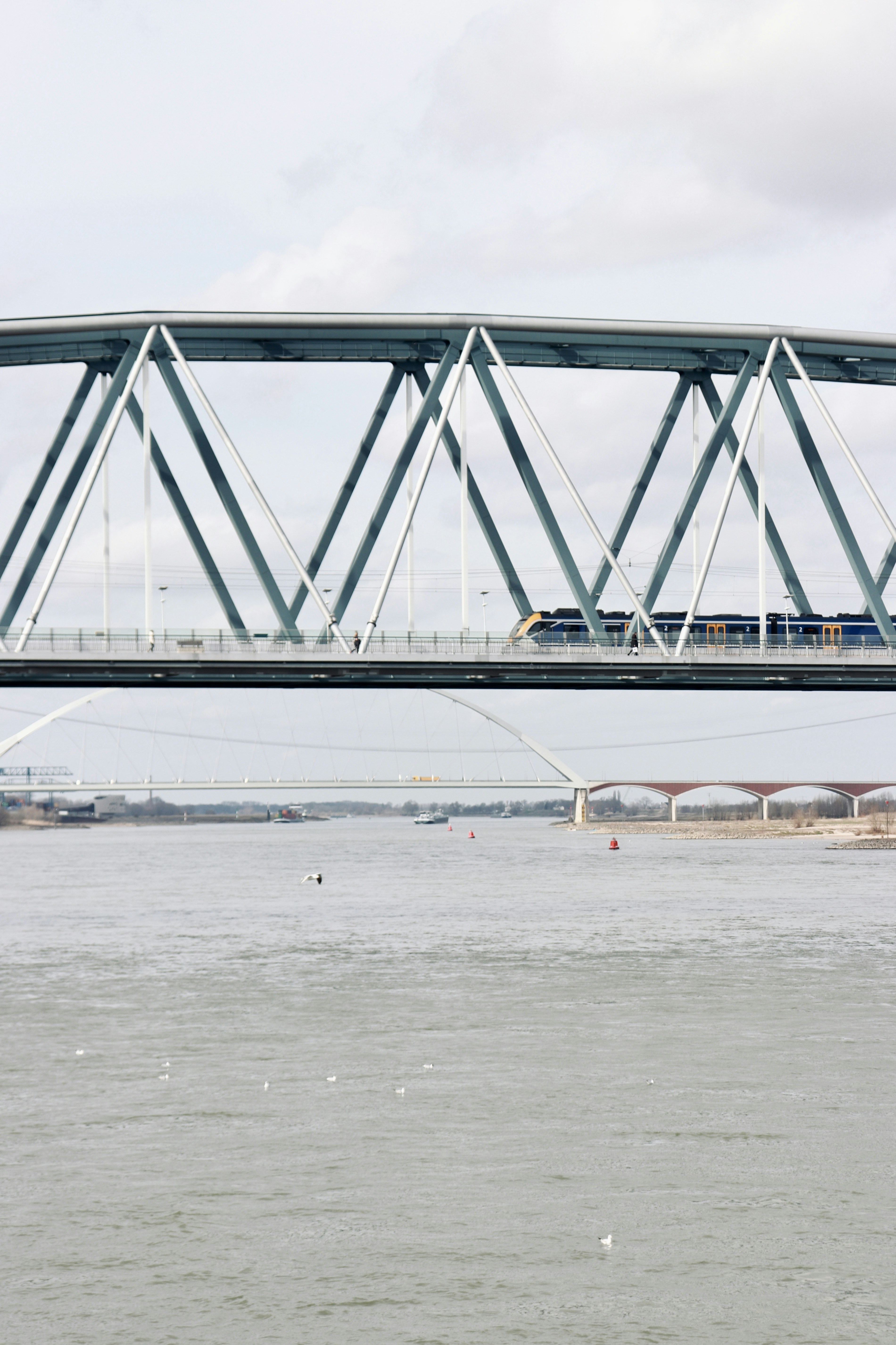 Blue-Truss Crossing: A Train Quietly Traverses a River Bridge