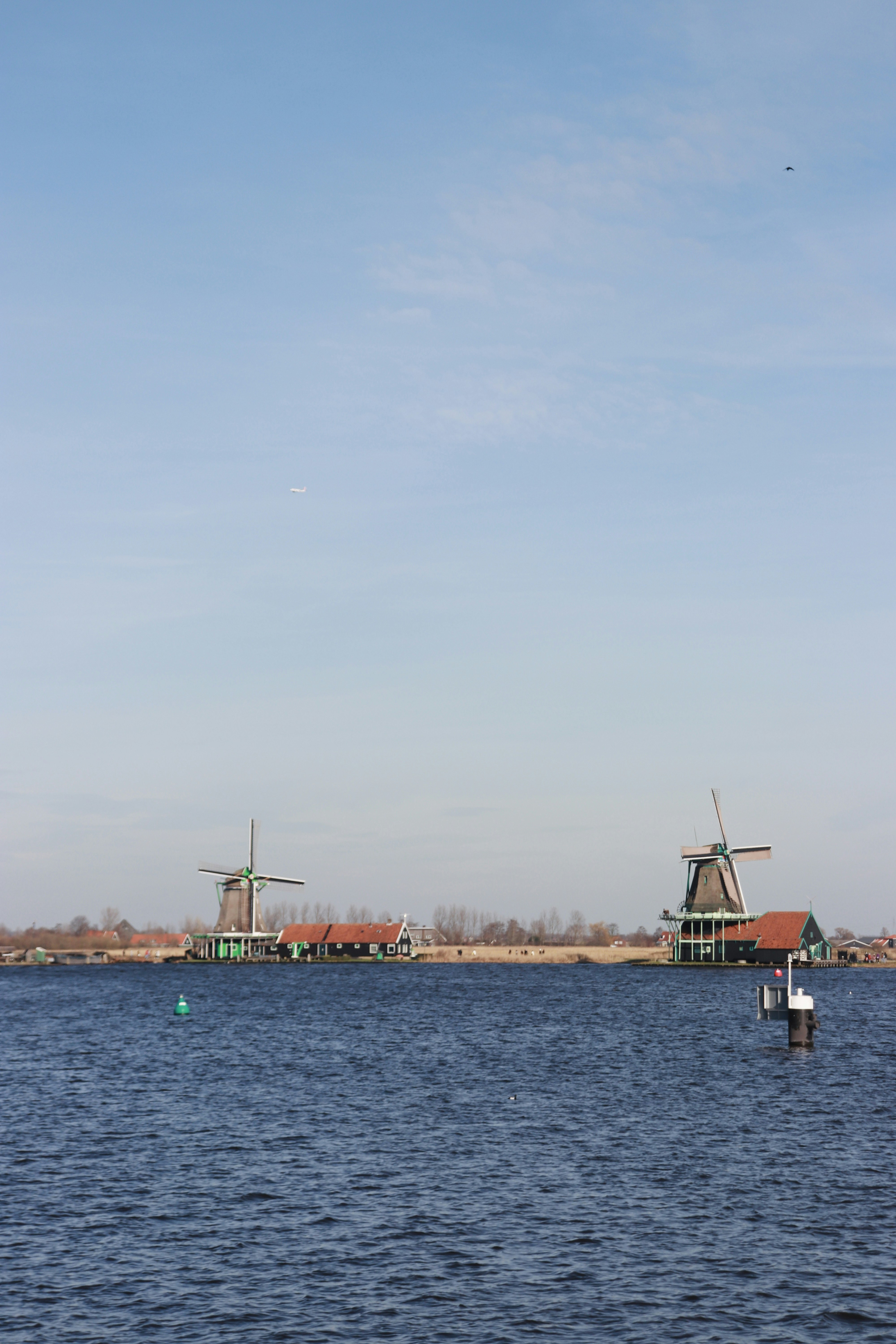 a body of water with buildings and windmills in the background