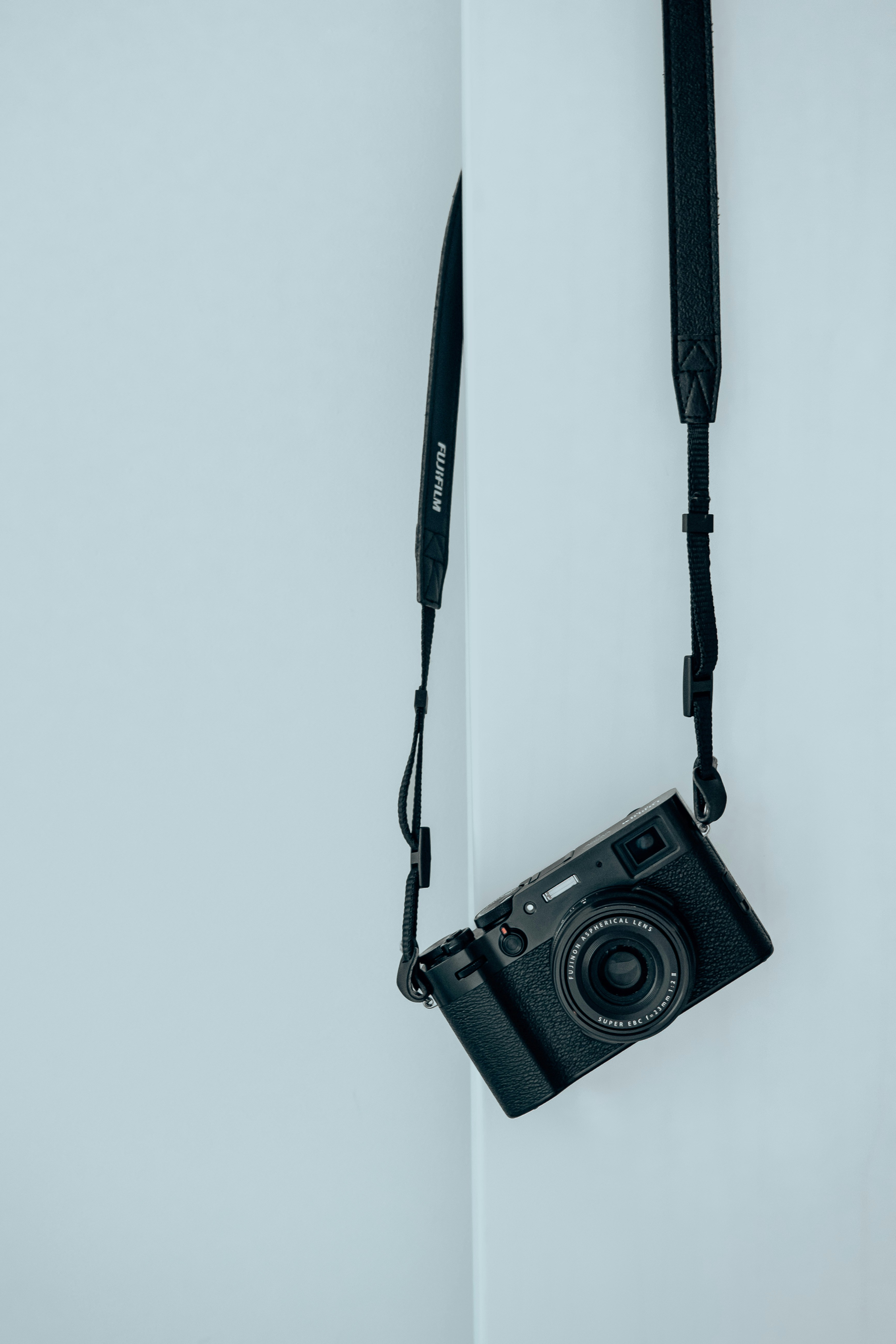 Fujifilm X-T4 camera hanging on a wall, showcasing its sleek design and minimalist aesthetic.