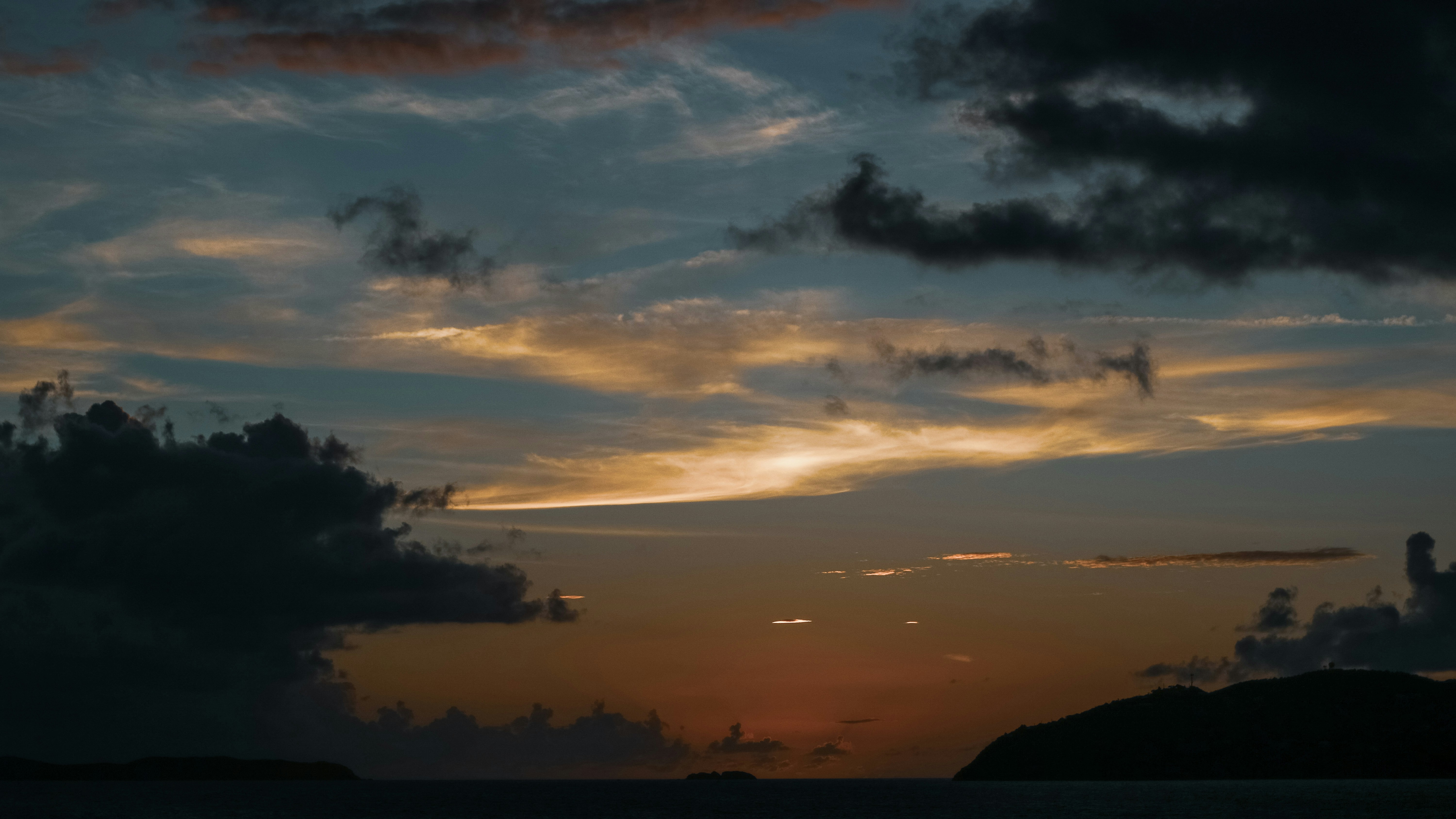 Horizon Ember: Sunset Over a Silhouetted Bay