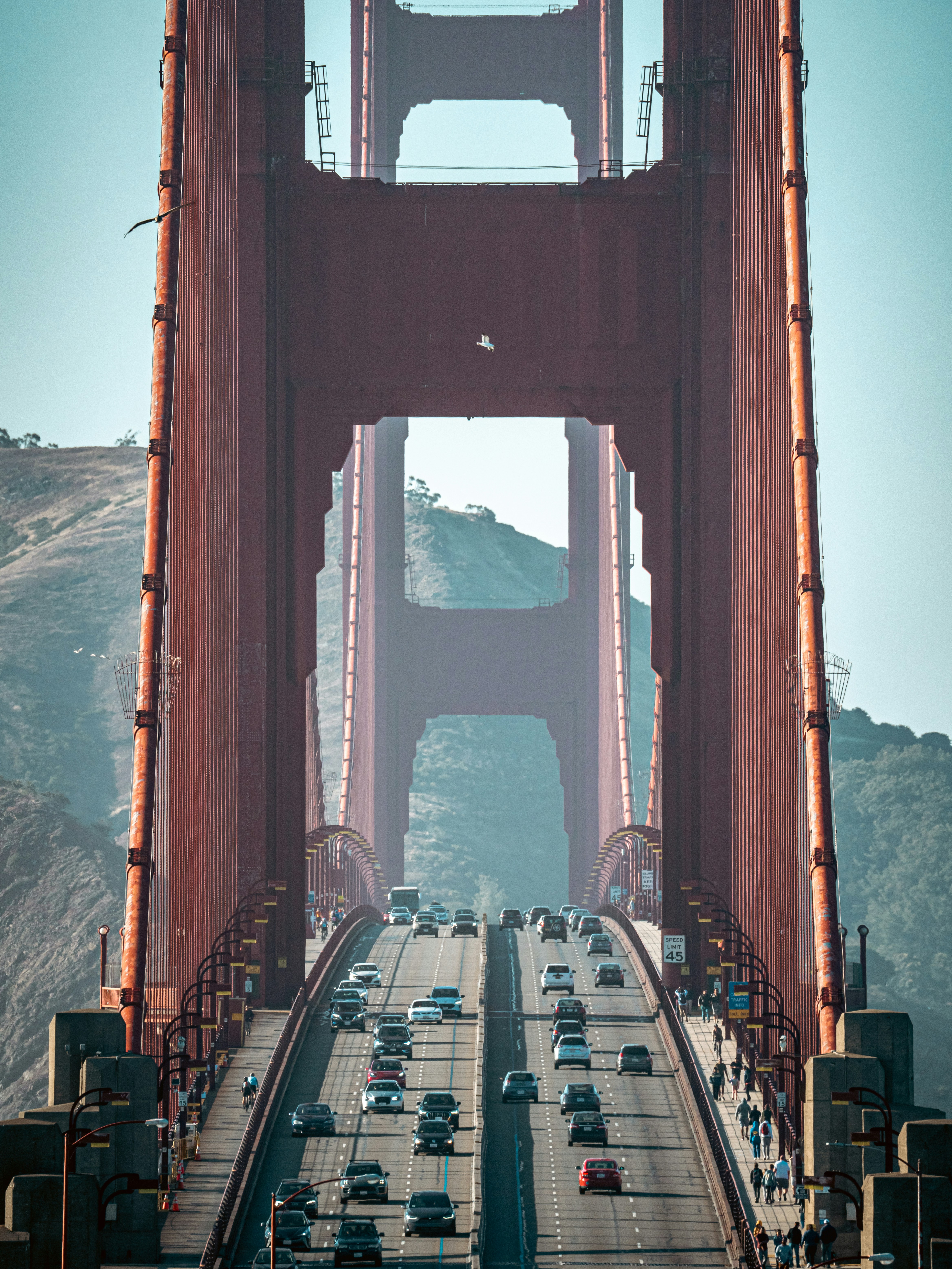 Golden Gate Bridge viewed from below, showcasing its towering structure and traffic flow. The image highlights the bridge's engineering and scenic backdrop.