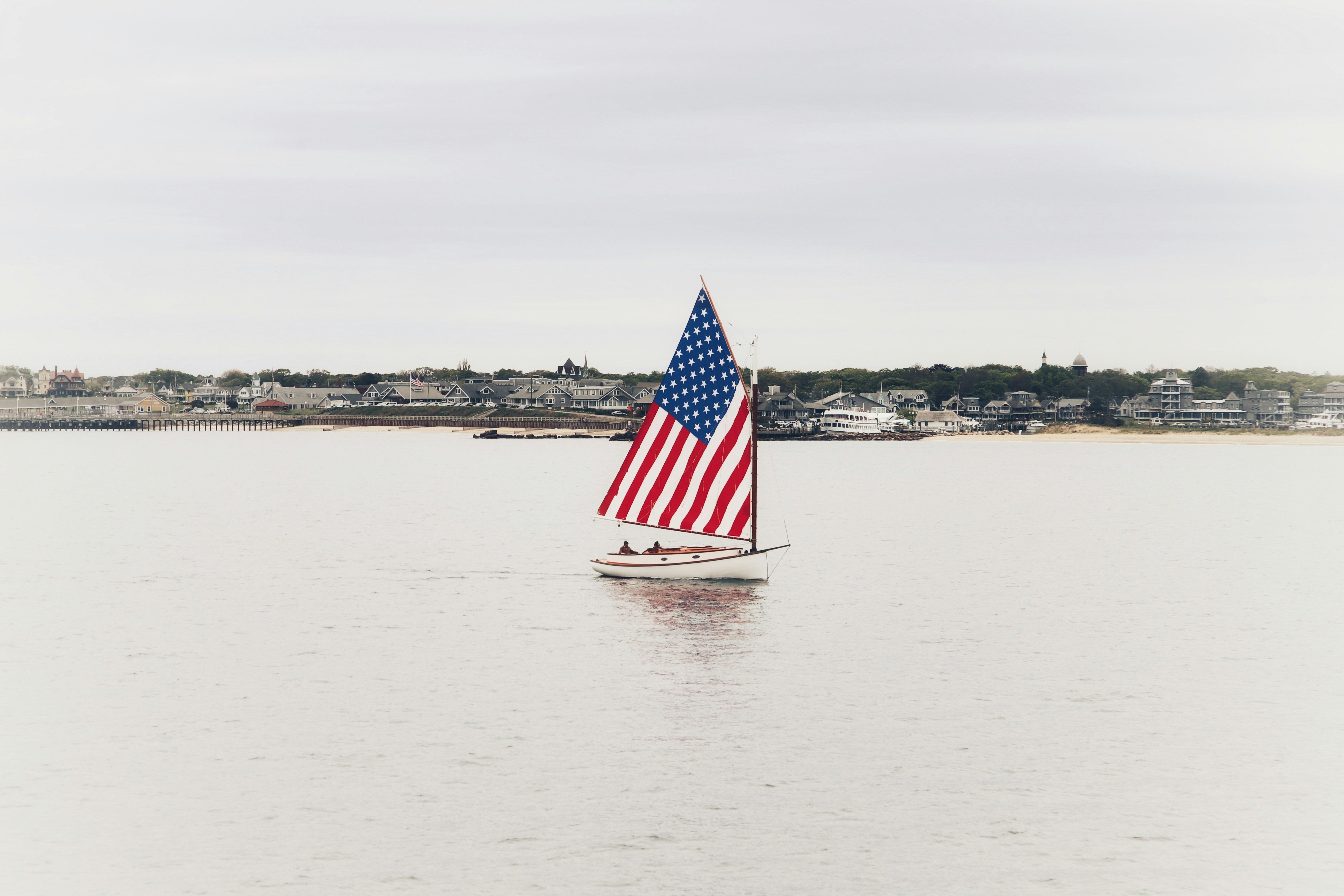 Flag-Tipped Sails Across a Quiet Bay