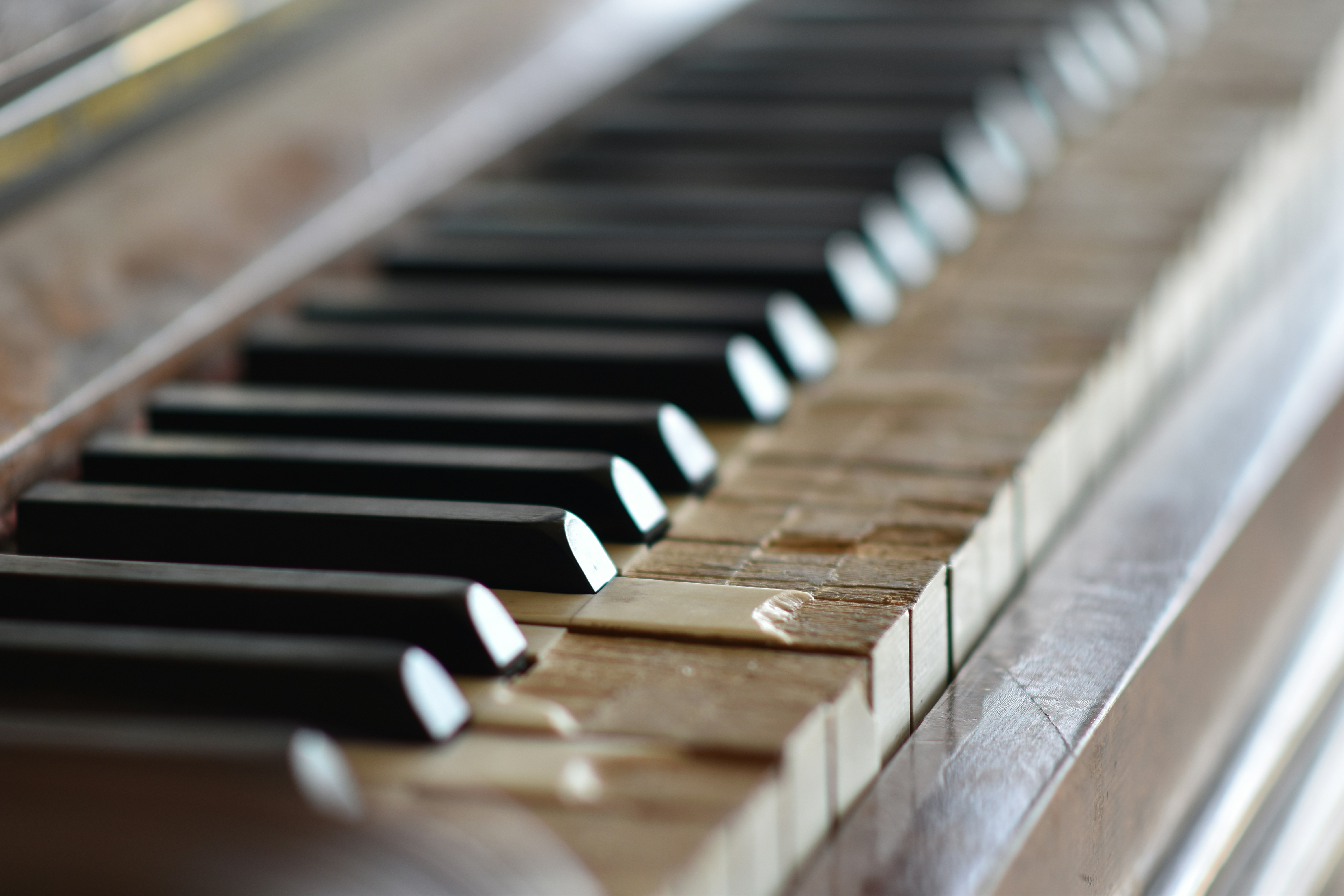 Close-up of piano keys showcasing the intricate details of worn ivory and polished wood. The image highlights the craftsmanship of the instrument.