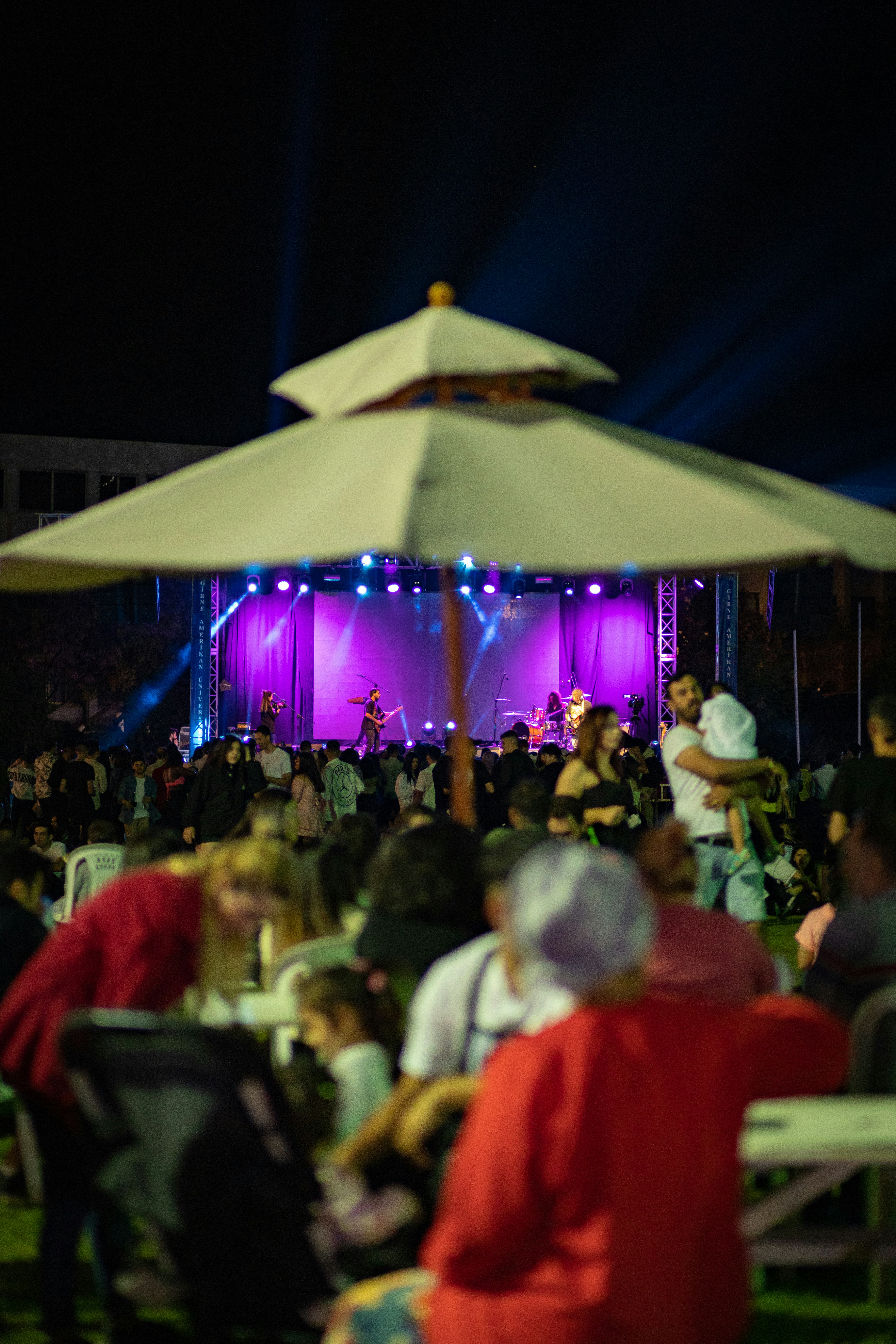 Under Green Umbrellas, Purple Stage Lights Illuminate a Night Concert