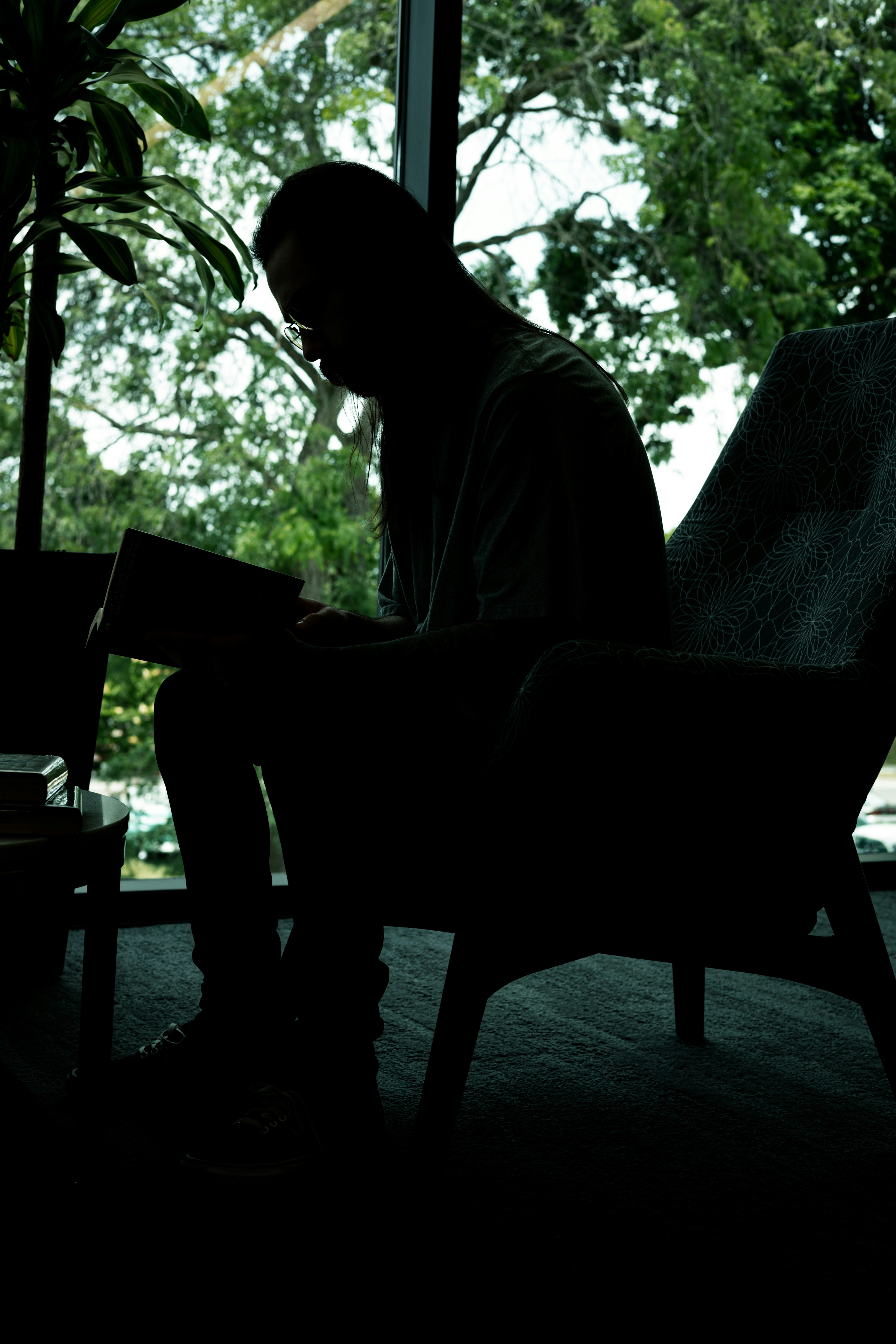 Window-Side Silhouette: A Quiet Reading Moment in Subtle Light