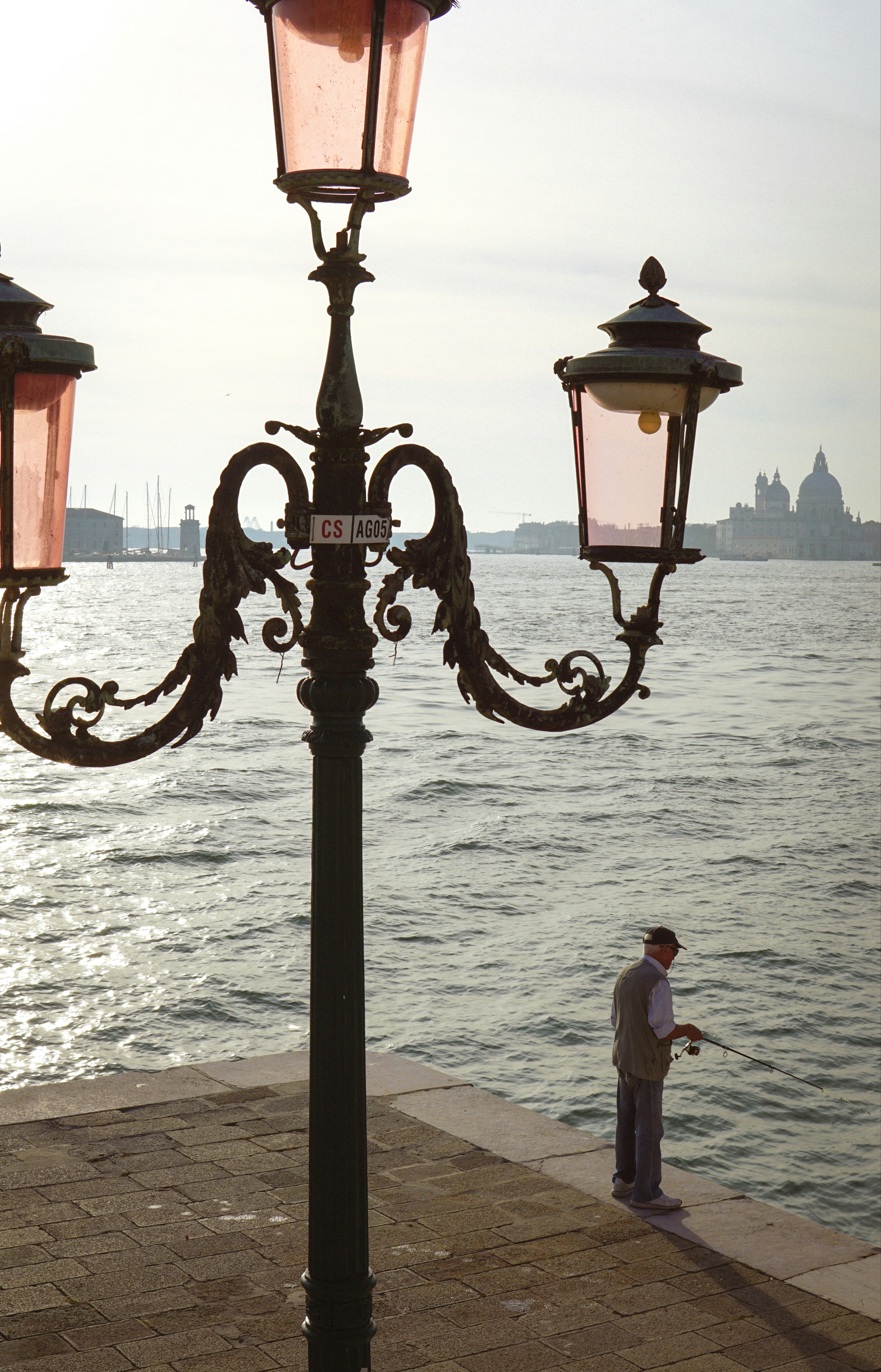 A man standing next to a lamp post by the water photo – Free Human ...
