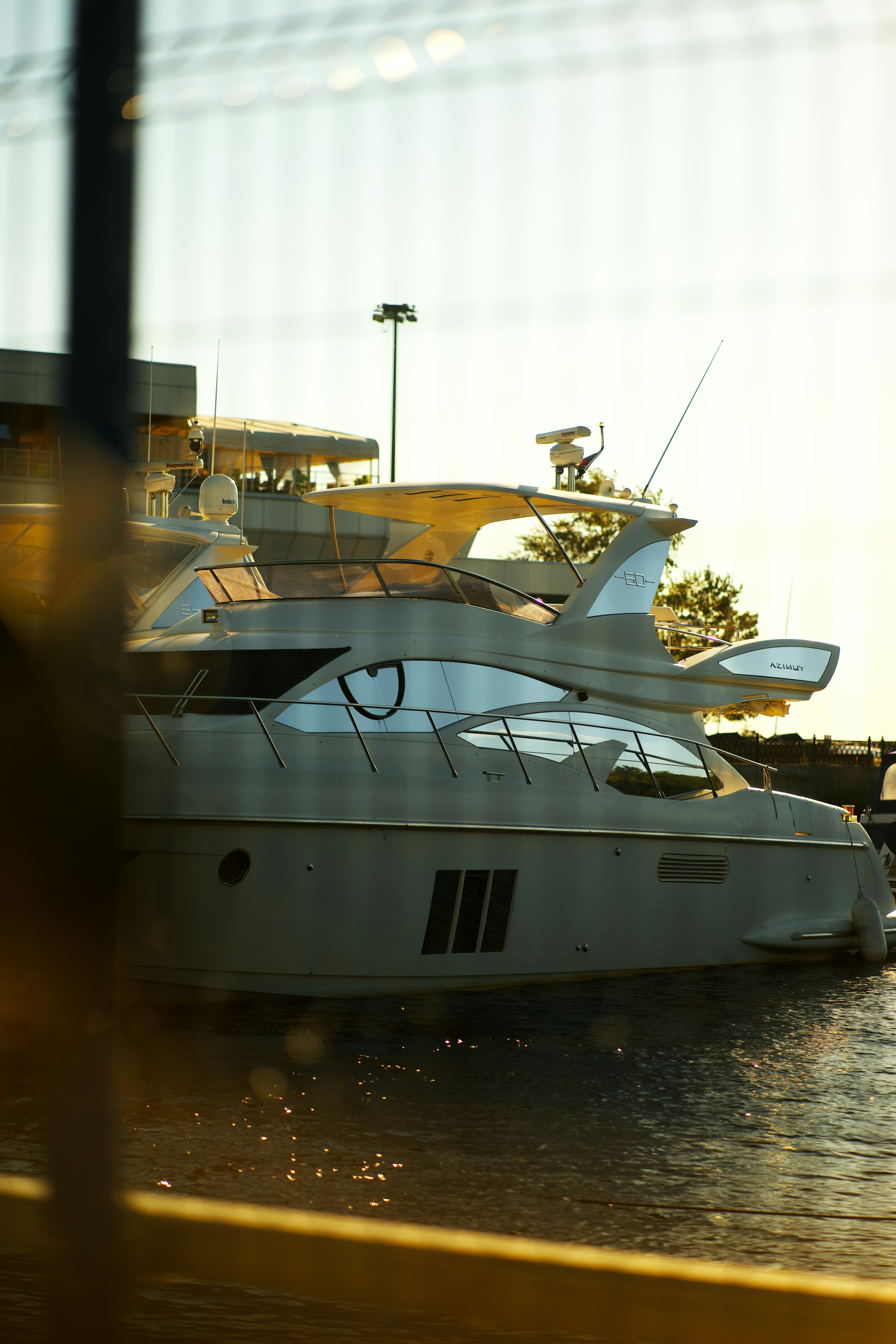 Luxury yacht docked at sunset, reflecting warm hues on the water's surface.