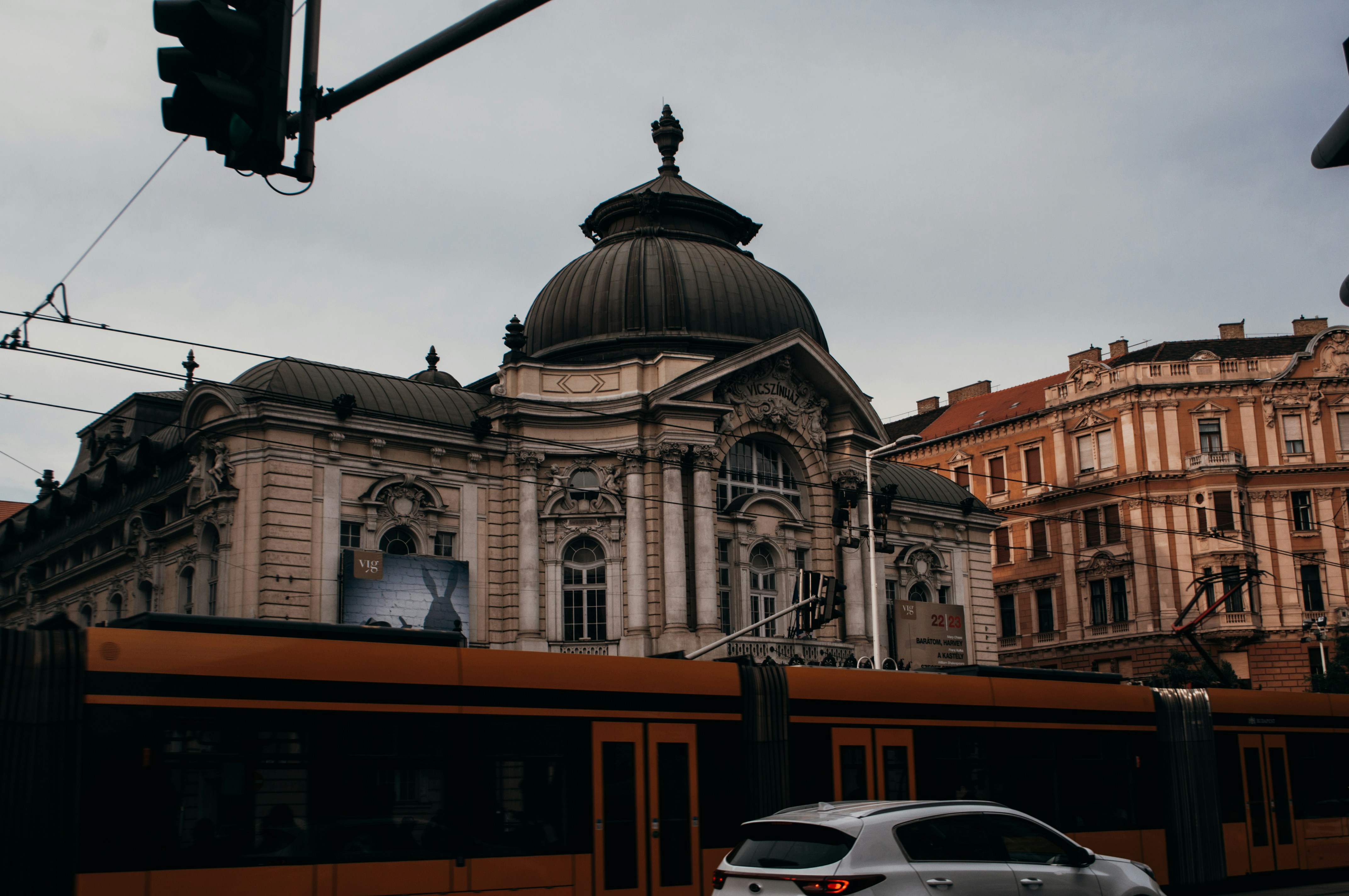 Historic building with a domed roof juxtaposed against a modern tram in a bustling city street.