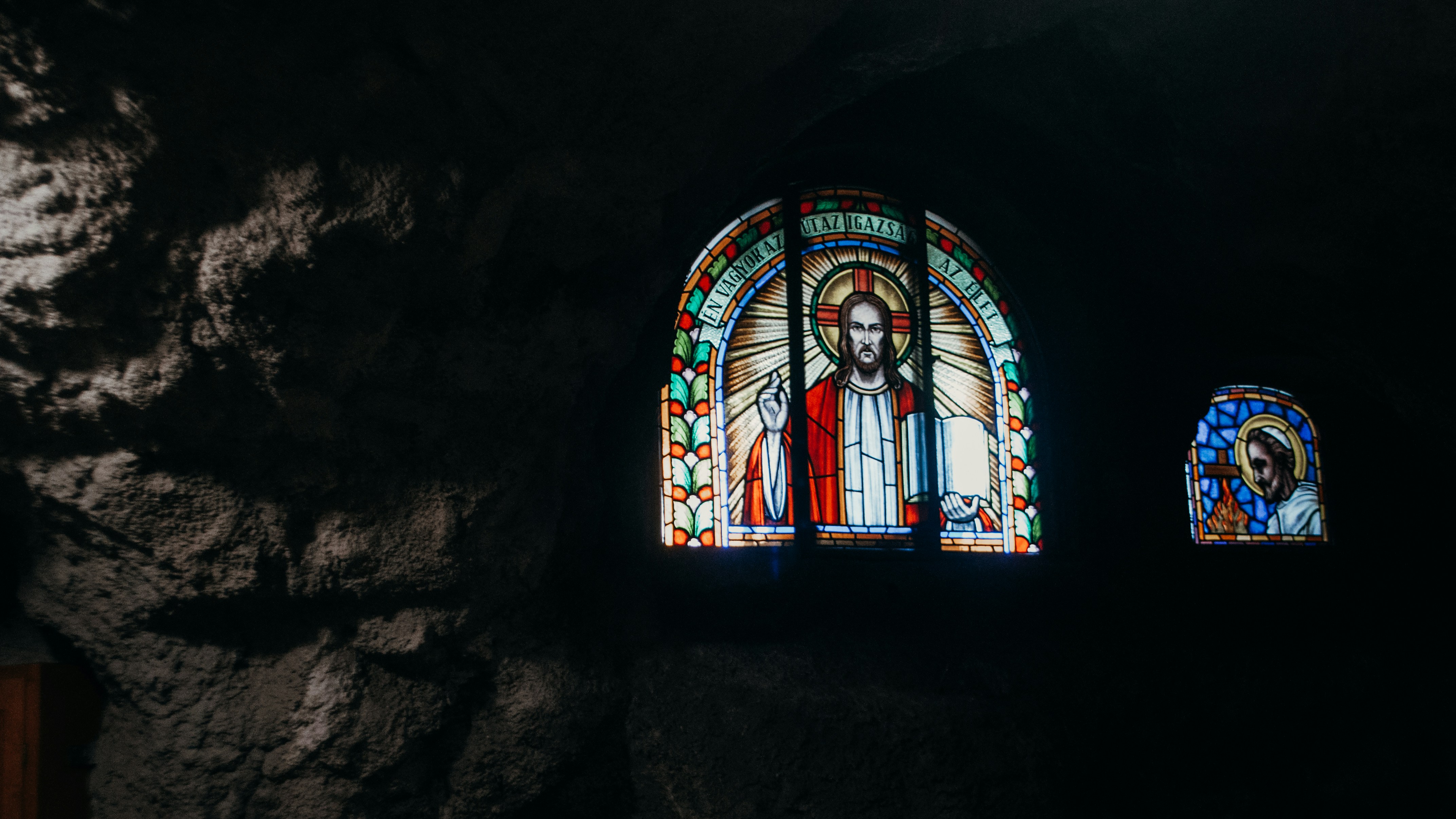 Stained glass windows depicting religious figures set against a dimly lit, rocky interior.