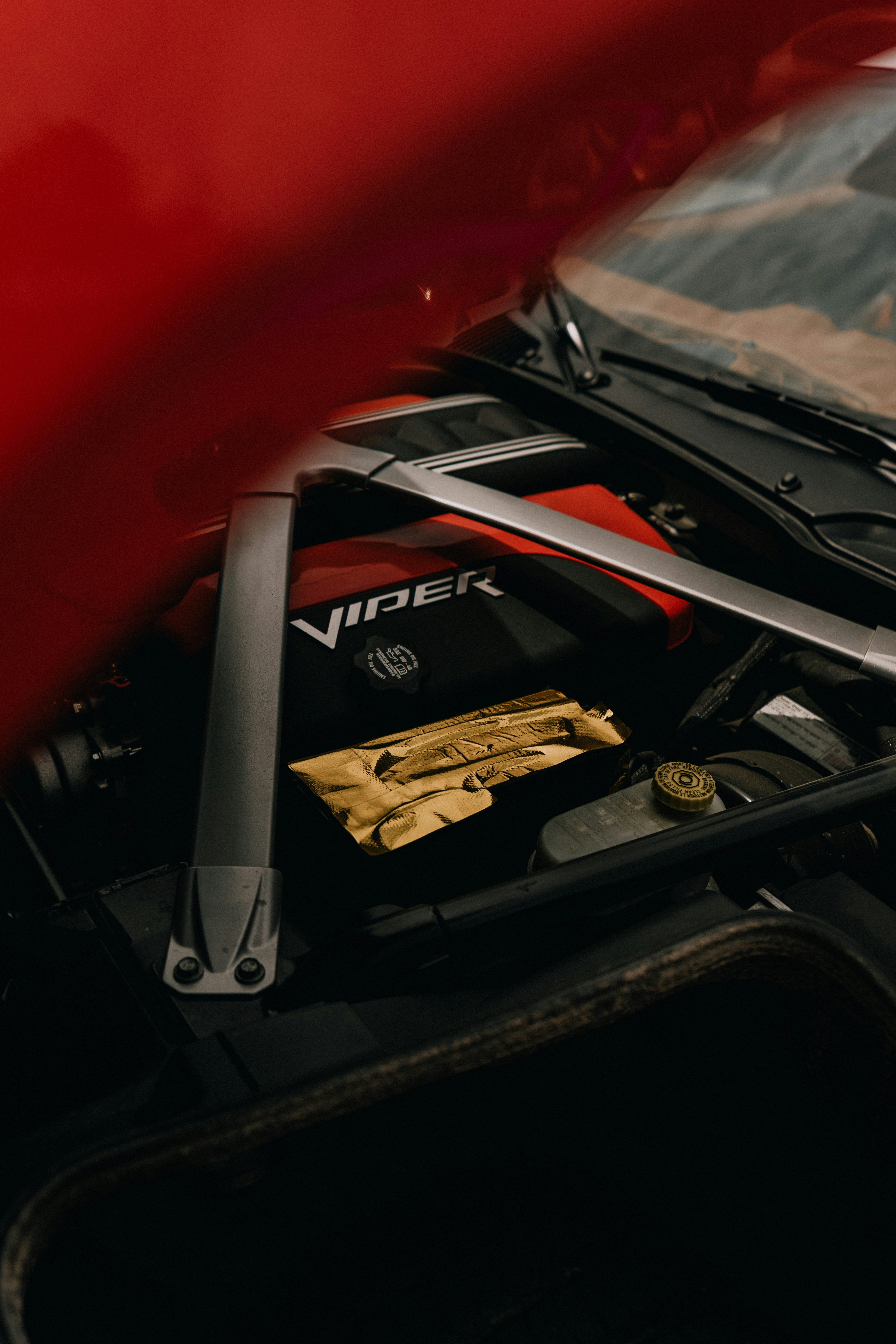 Close-up of a high-performance engine with Viper branding under a red car hood.