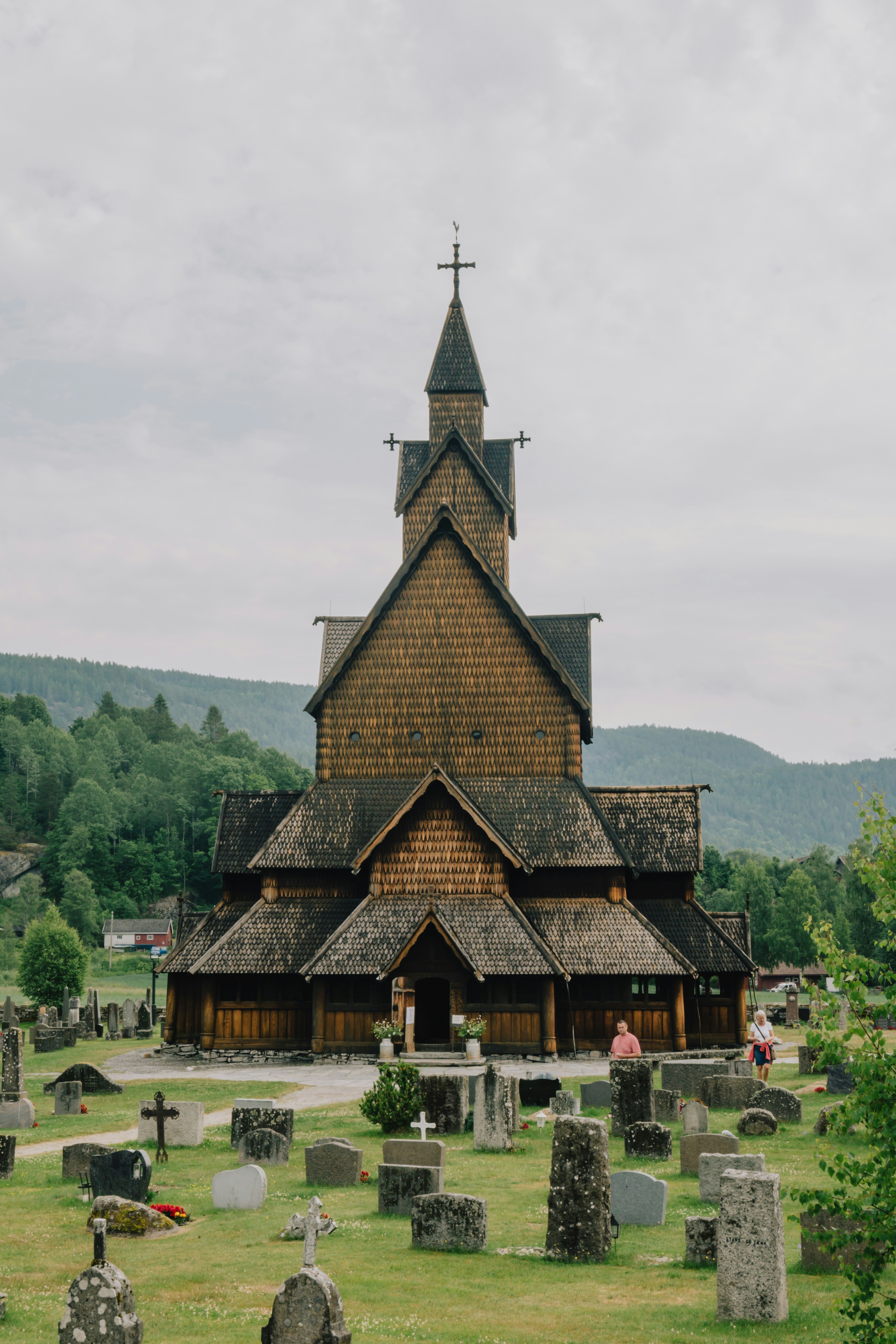 Intricate wooden church structure surrounded by gravestones in a serene landscape, showcasing traditional craftsmanship.