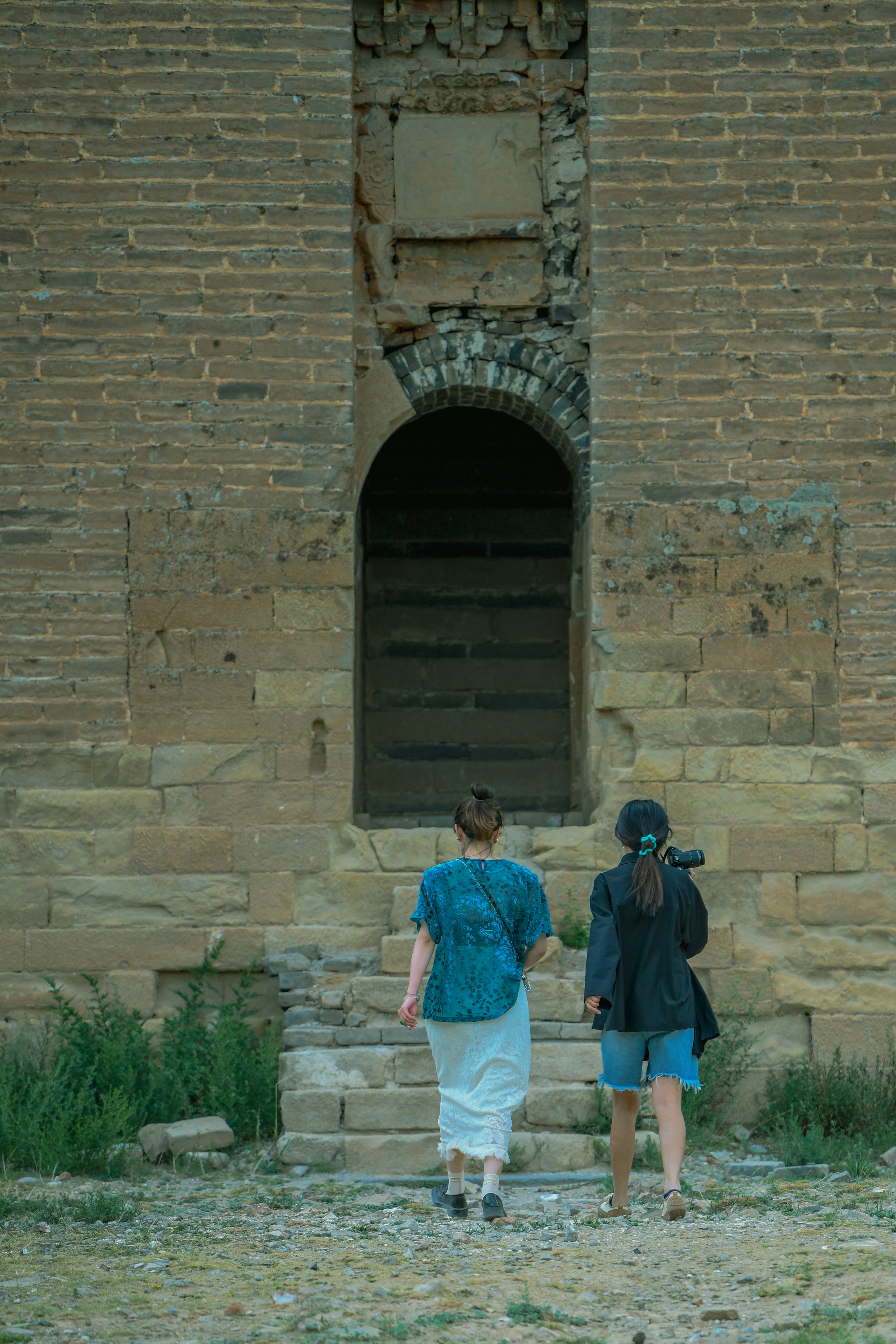 Two travelers Step Toward an Ancient Archway