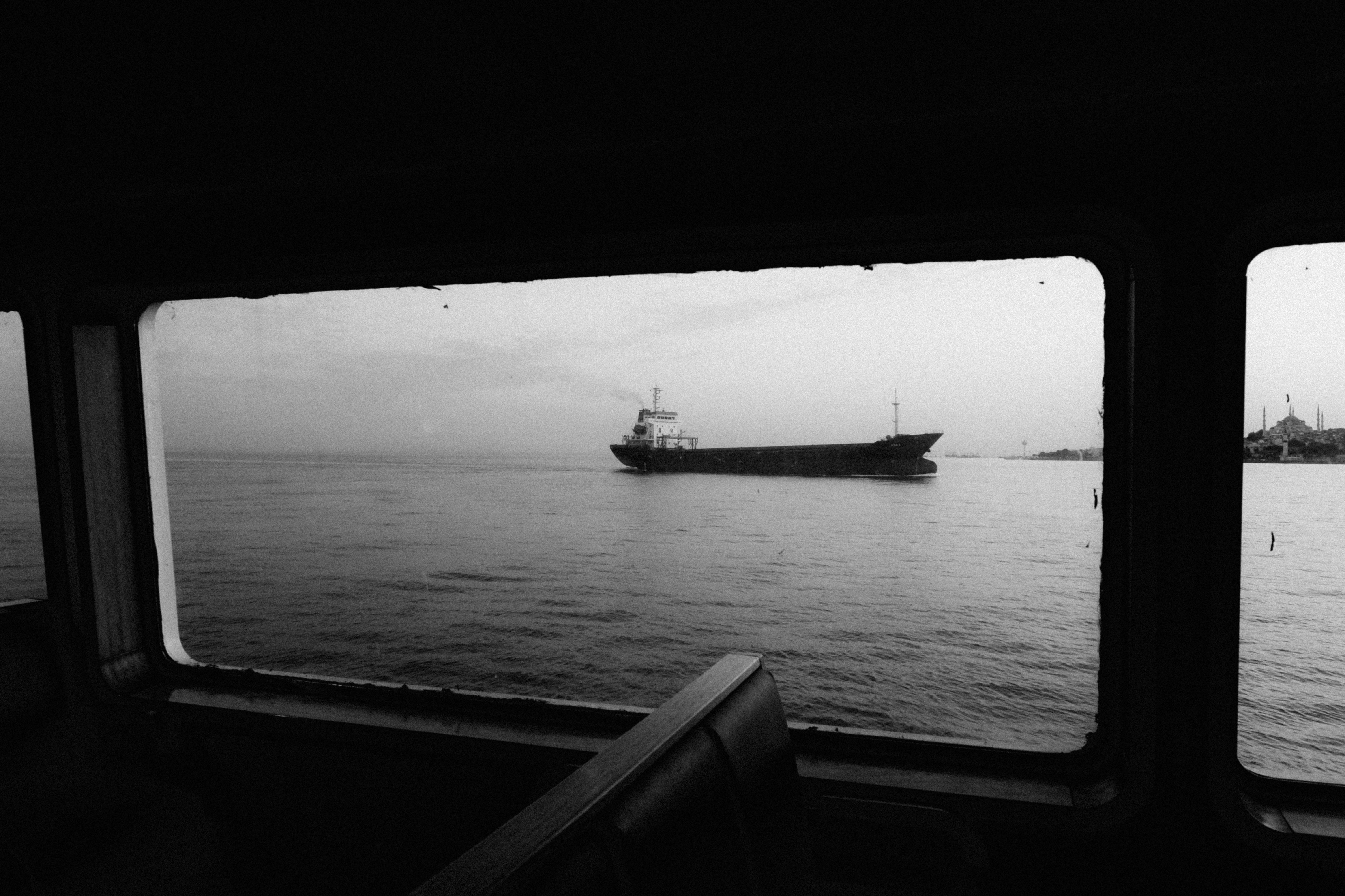 Horizon Frame: Cargo Vessel Through a Shadowed Cabin Window