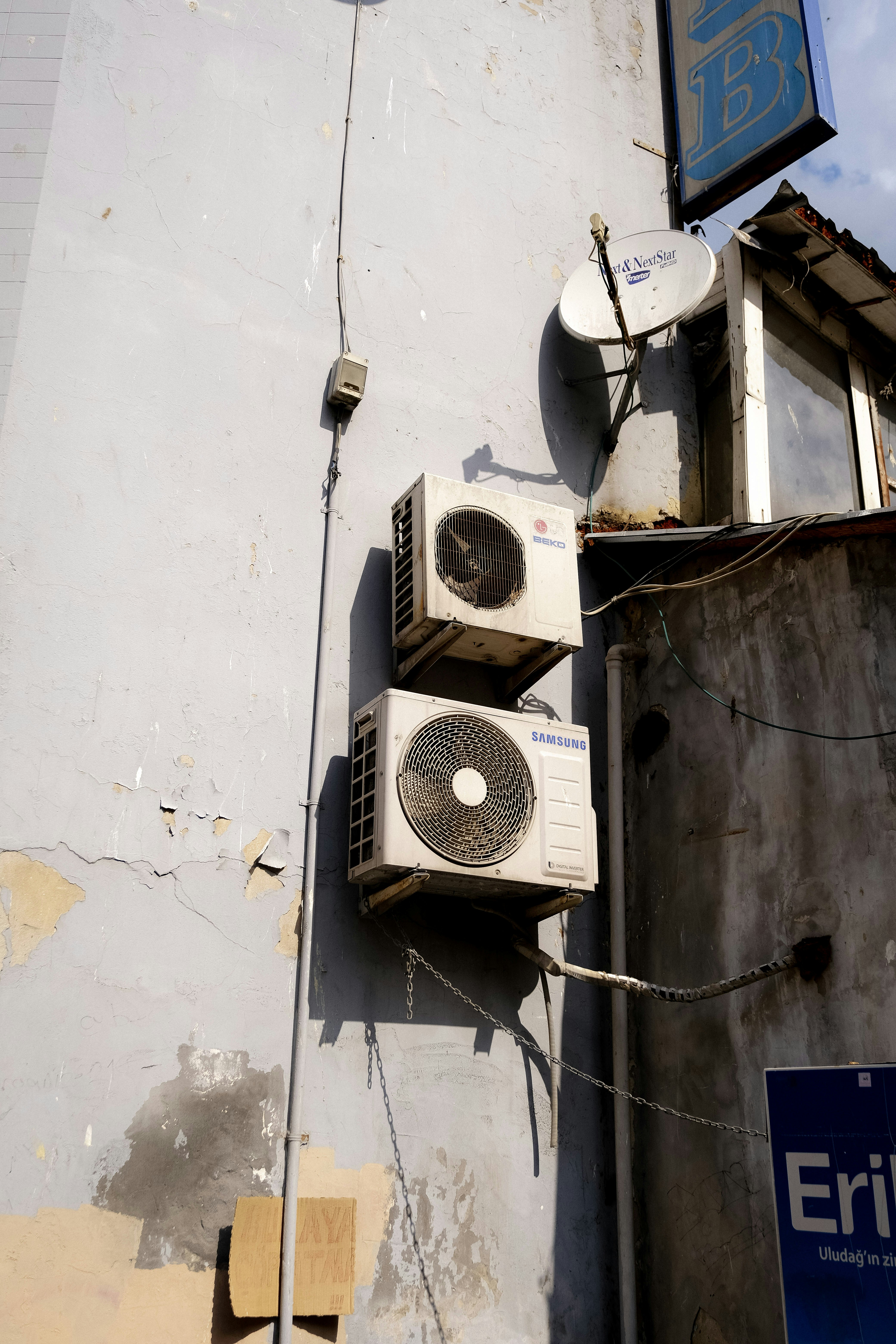 Two air conditioning units mounted on a weathered wall, showcasing urban life and the need for comfort in bustling environments.