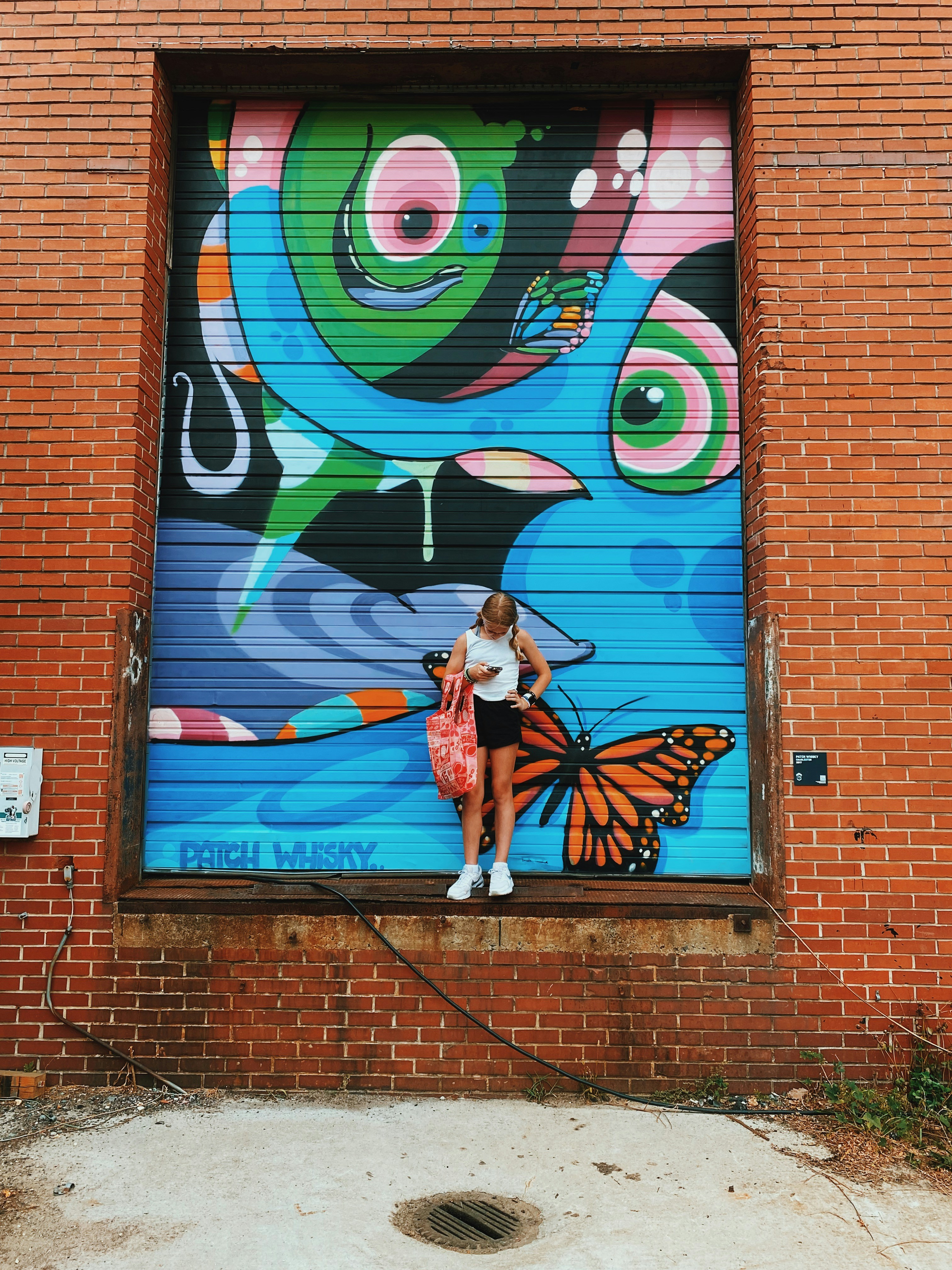 Girl in White Sneakers Beneath a Butterfly Graffiti Mosaic