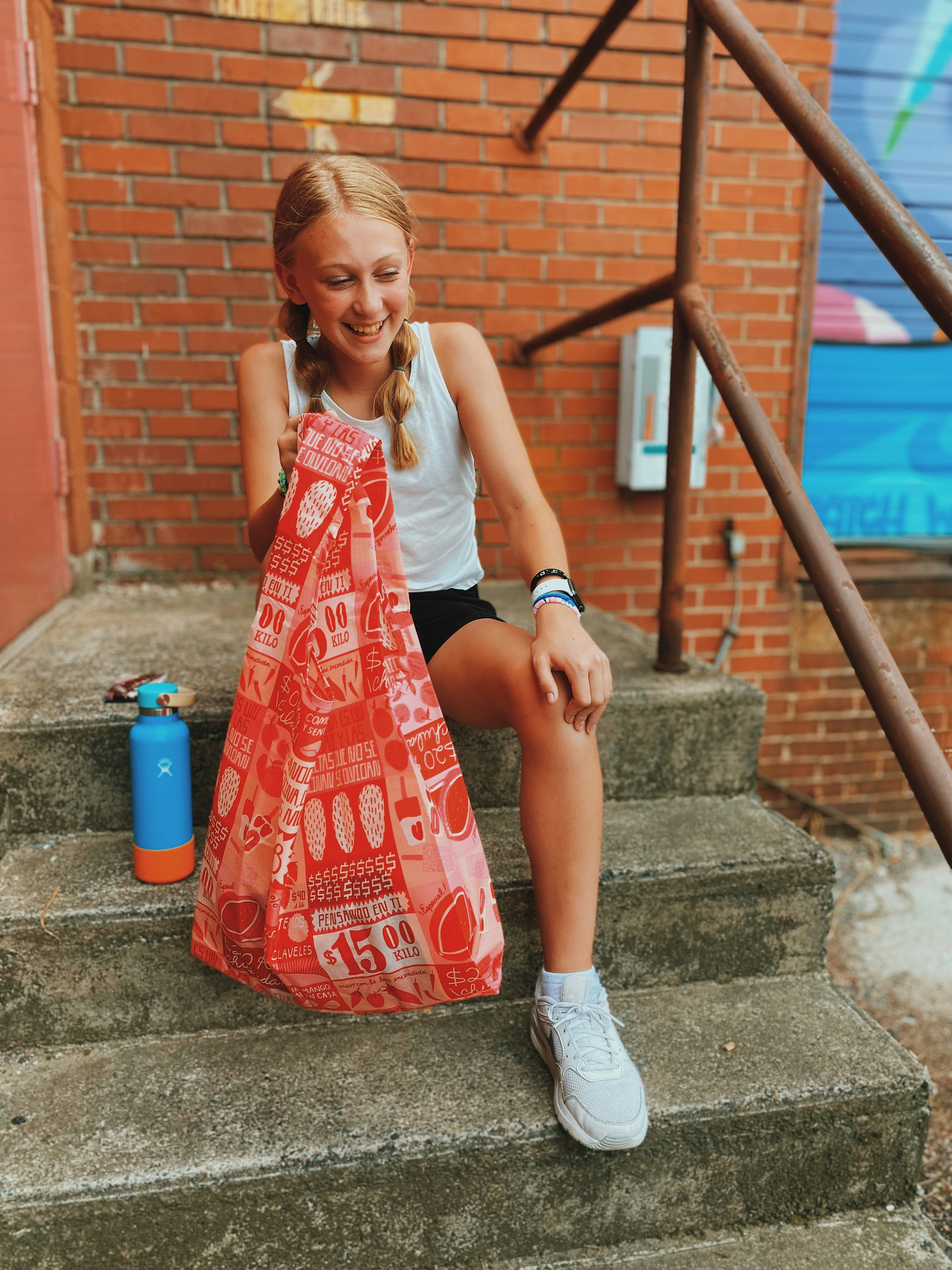 Red-Printed Tote and a Warm Smile on Brick Staircase
