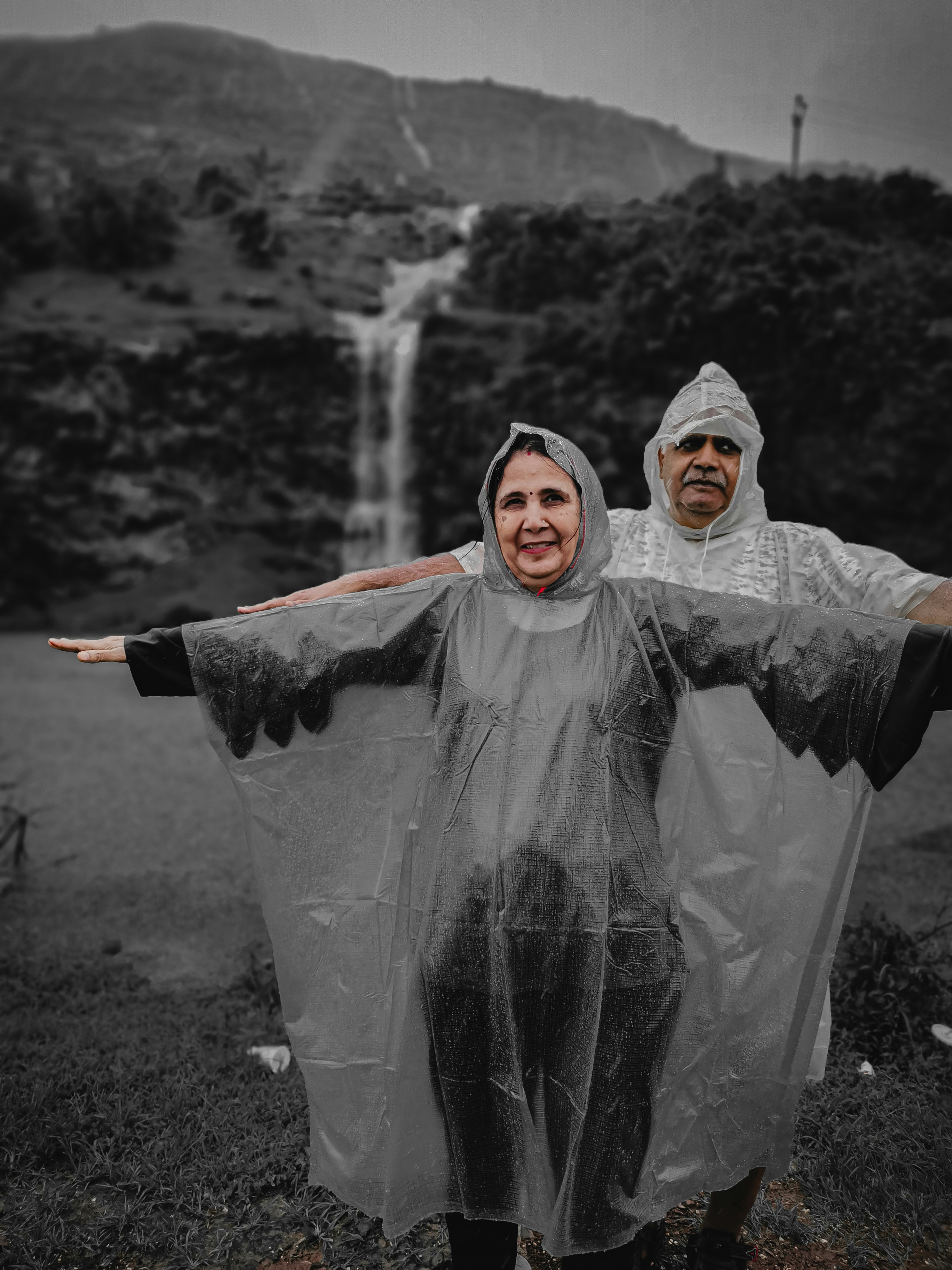 Two ponchos under a cascade: a rain-washed portrait at the waterfall
