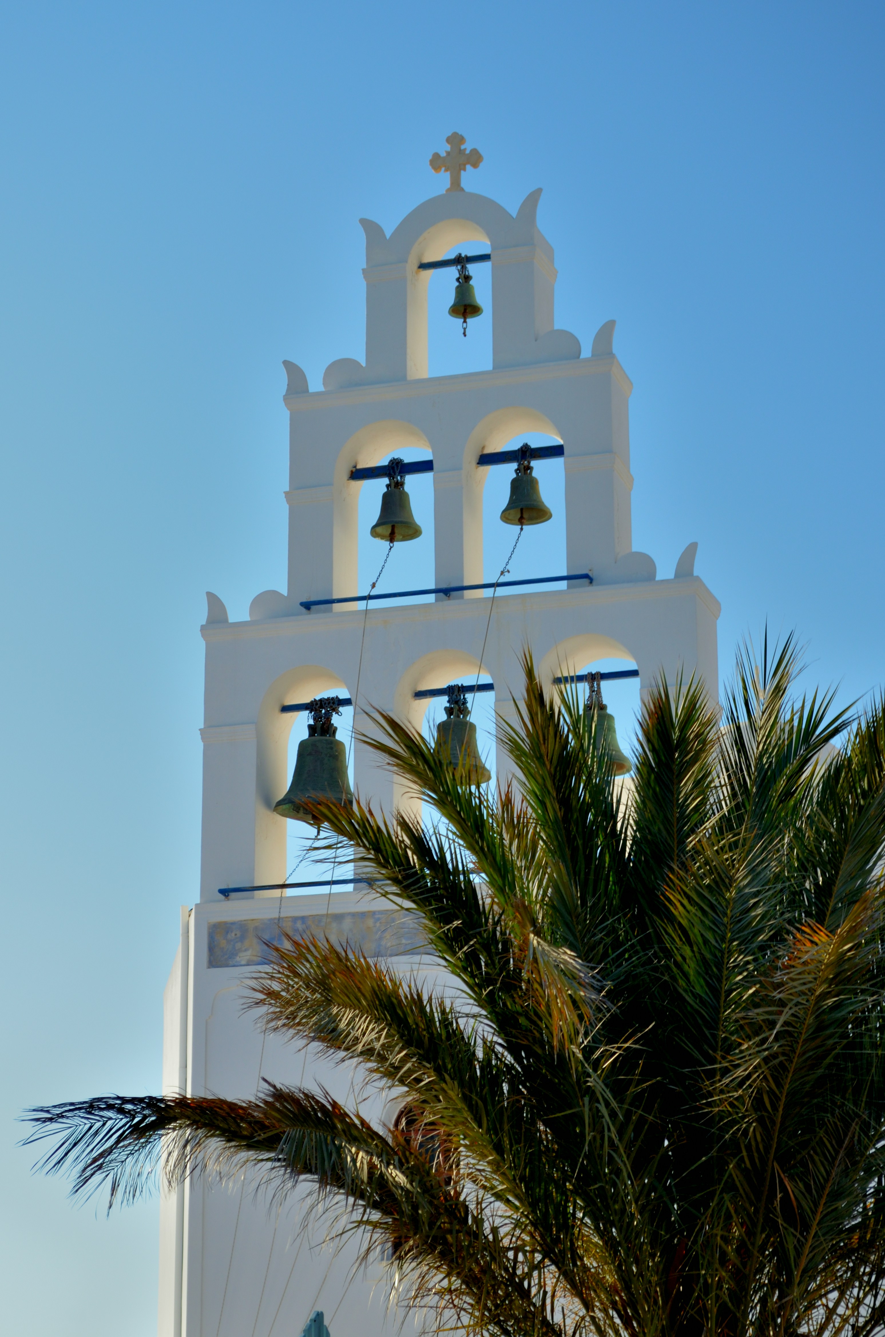 Cobalt-Trim Bell Tower Rising Over Palm Fronds in Aegean Light
