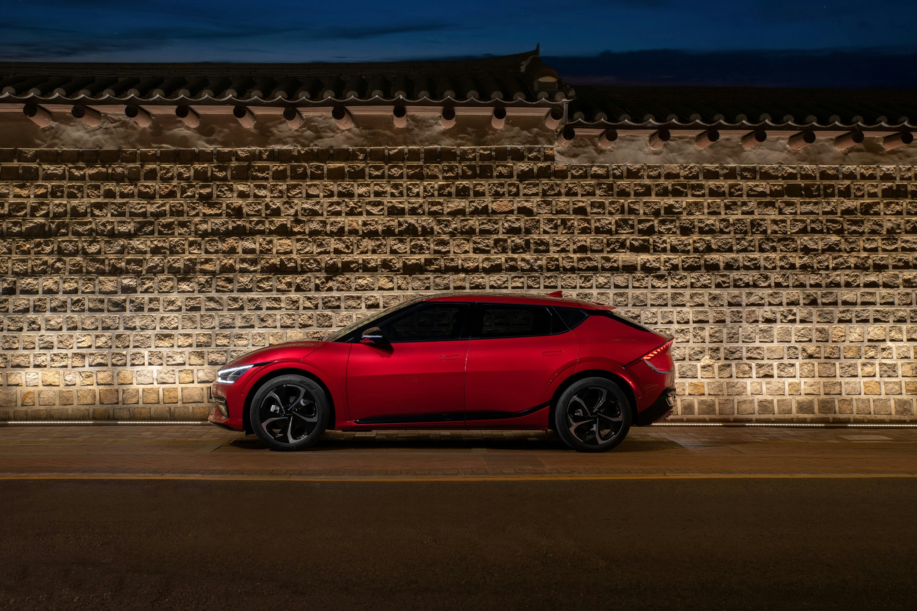 A red car parked in front of a stone wall photo – Free Car Image on ...