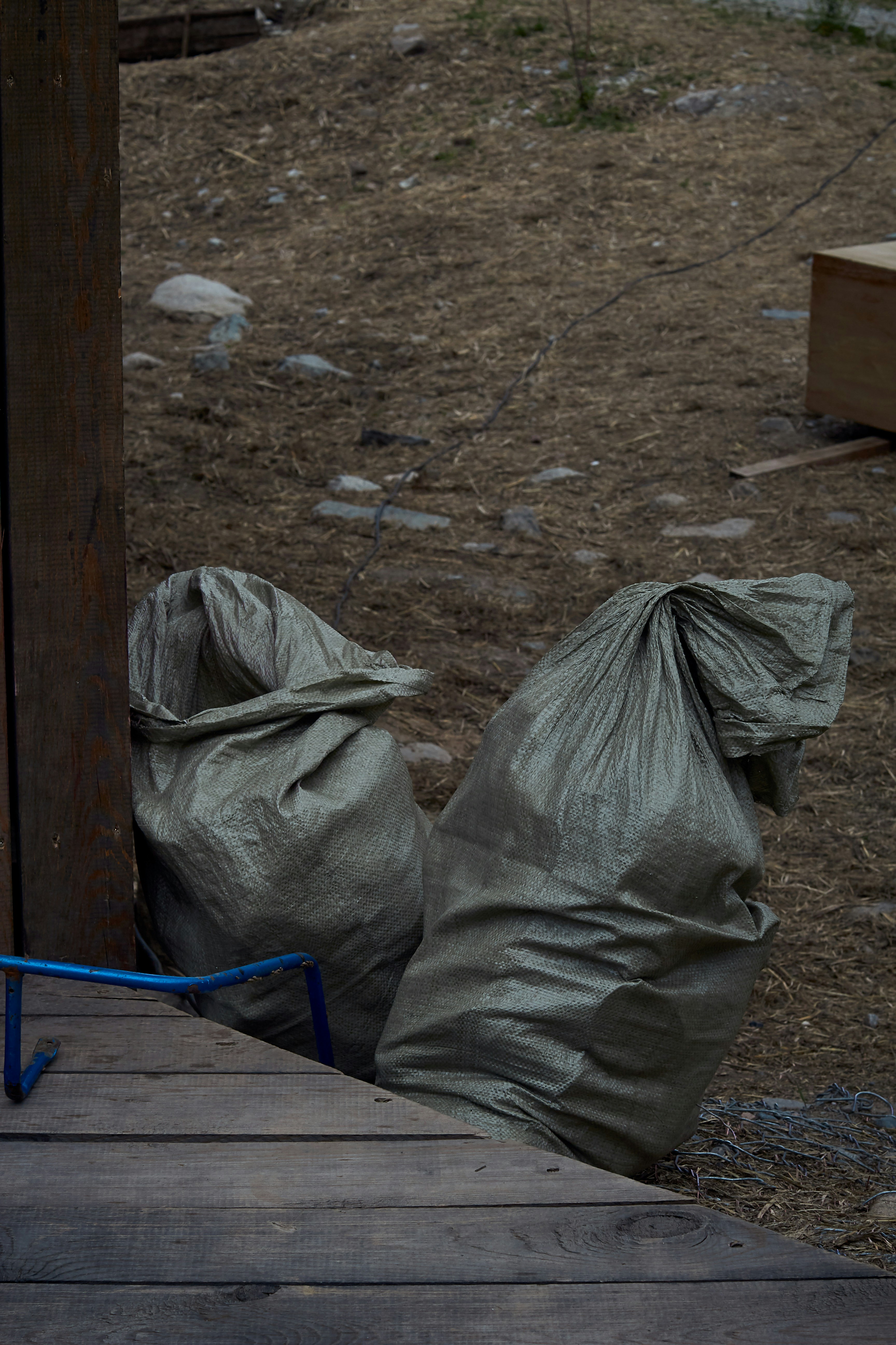 Weathered Tarpaulin Sacks Guard a Wooden Platform in a Quiet Yard