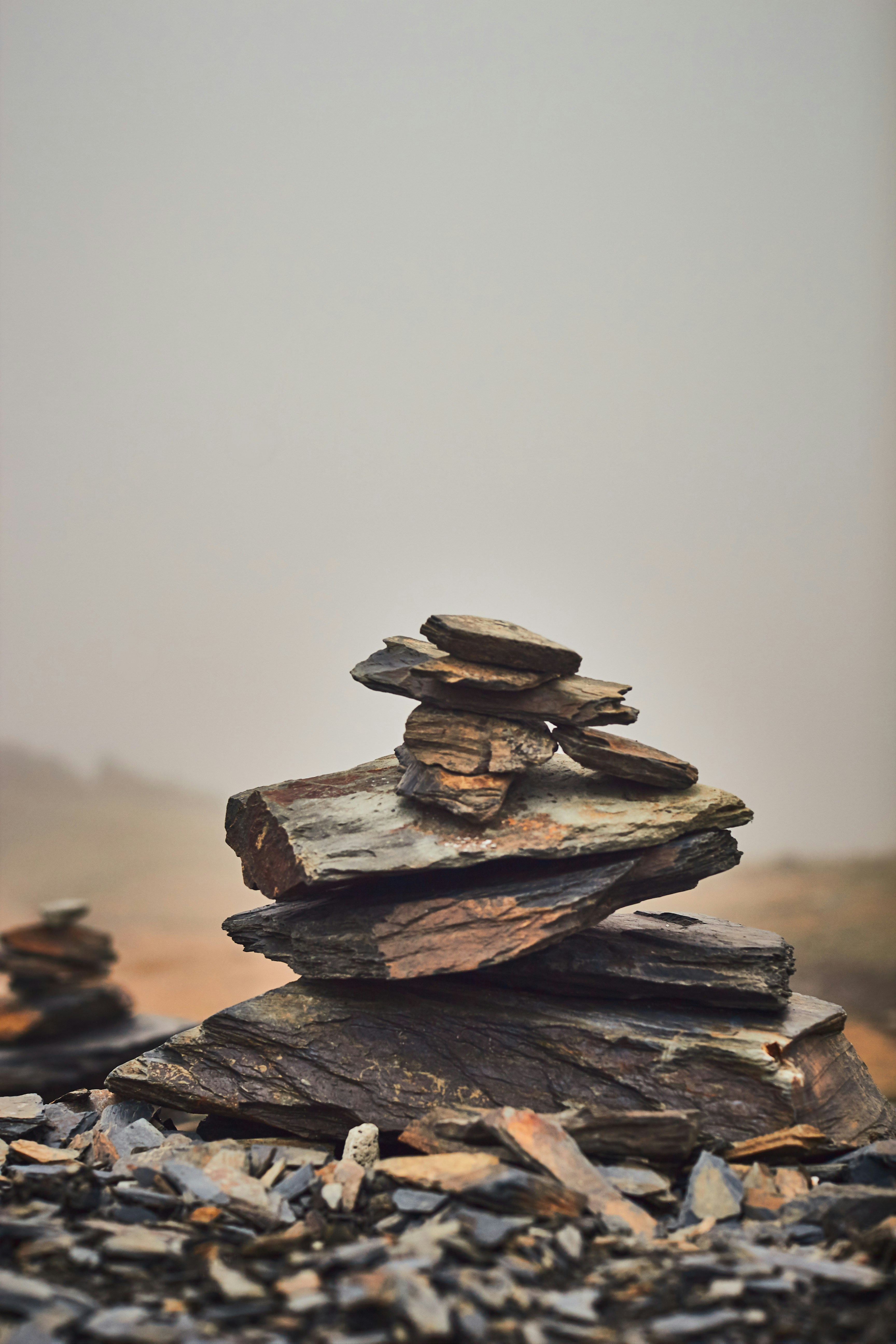 A carefully balanced stack of stones rises amidst a foggy landscape, symbolizing nature's artistry and human connection. The muted background adds a sense of tranquility.
