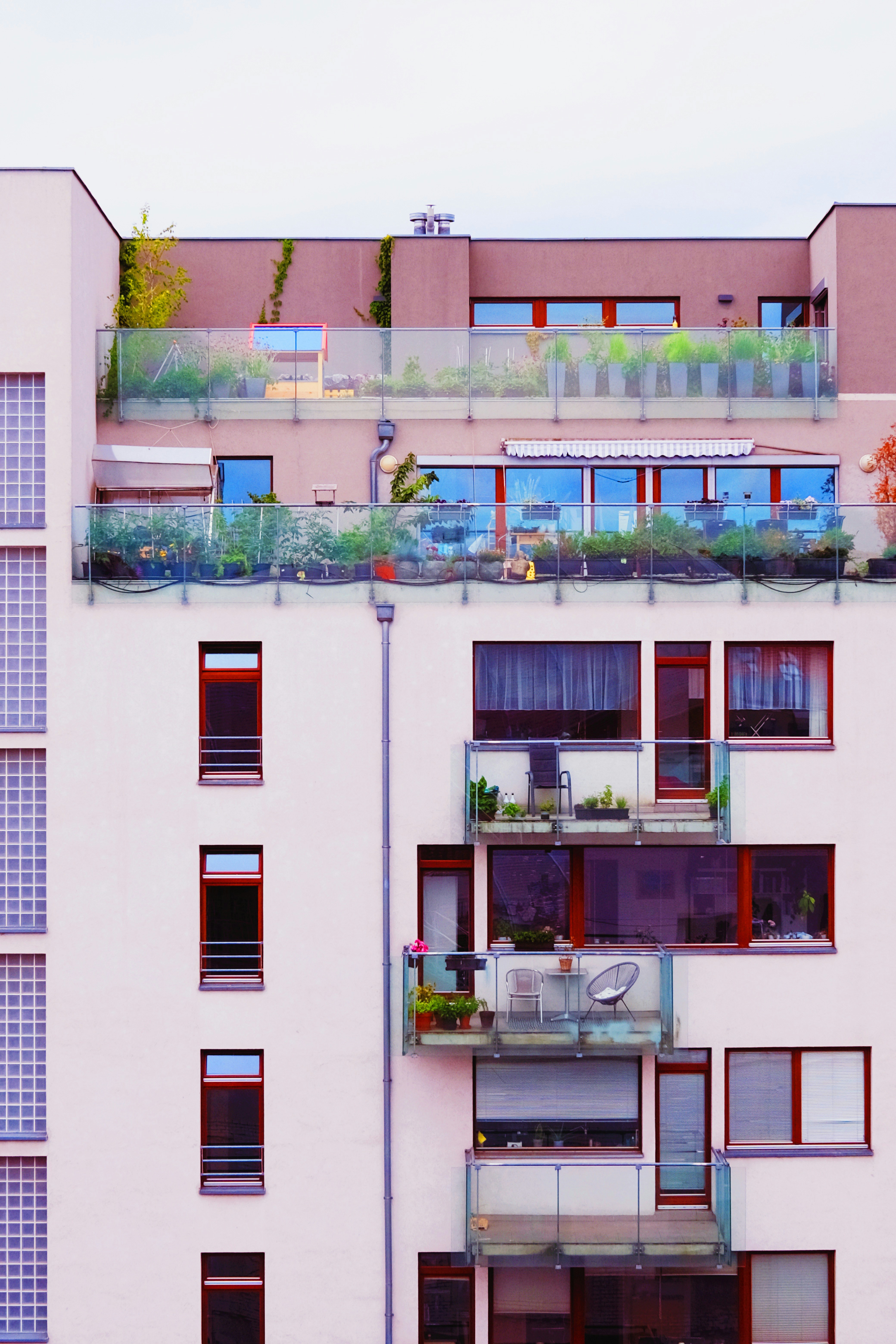 Verdant Tiers on a Pastel Facade: Glass Balconies and Urban Green