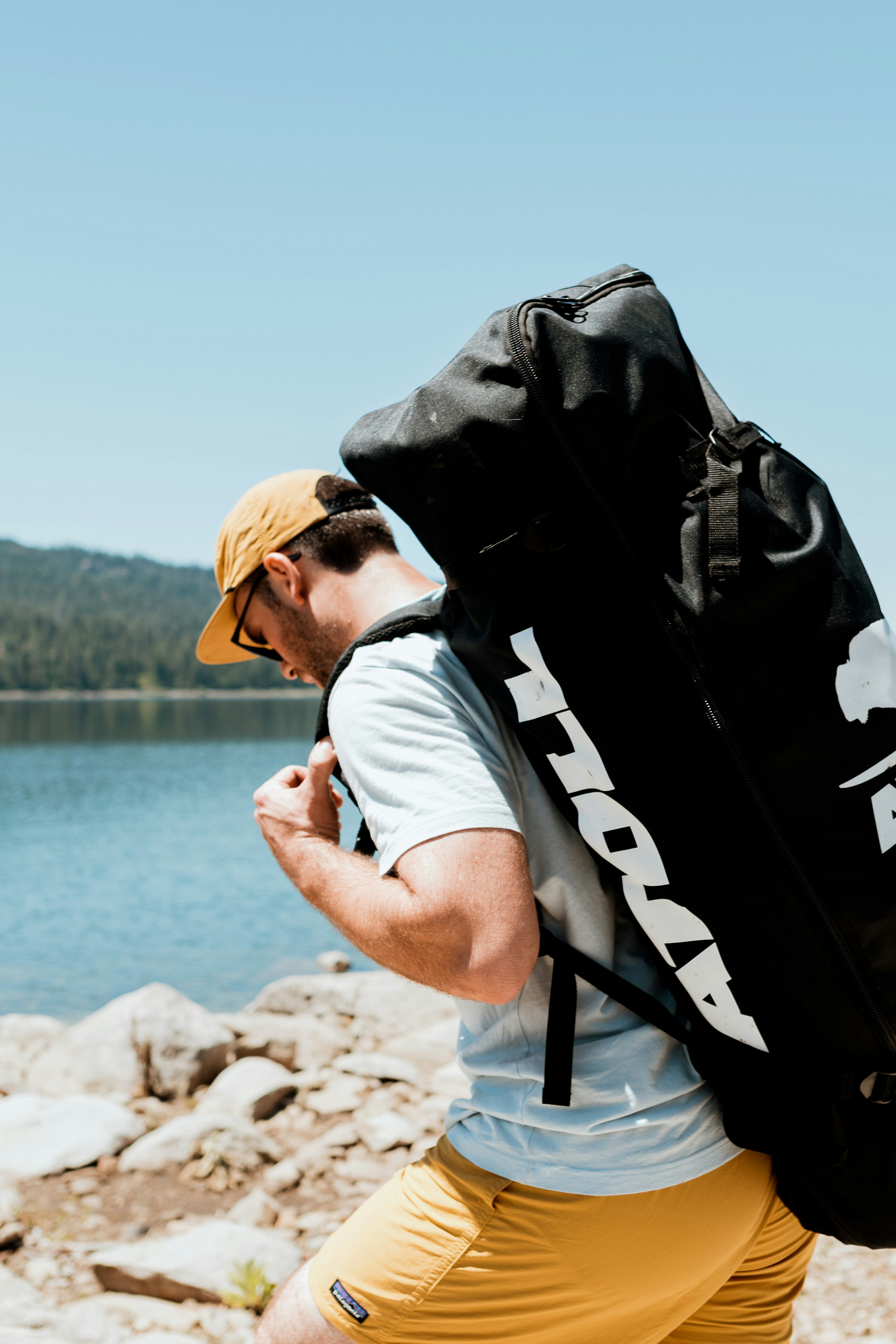 Overland ascent: the lone traveler balances gear against a blue alpine lake