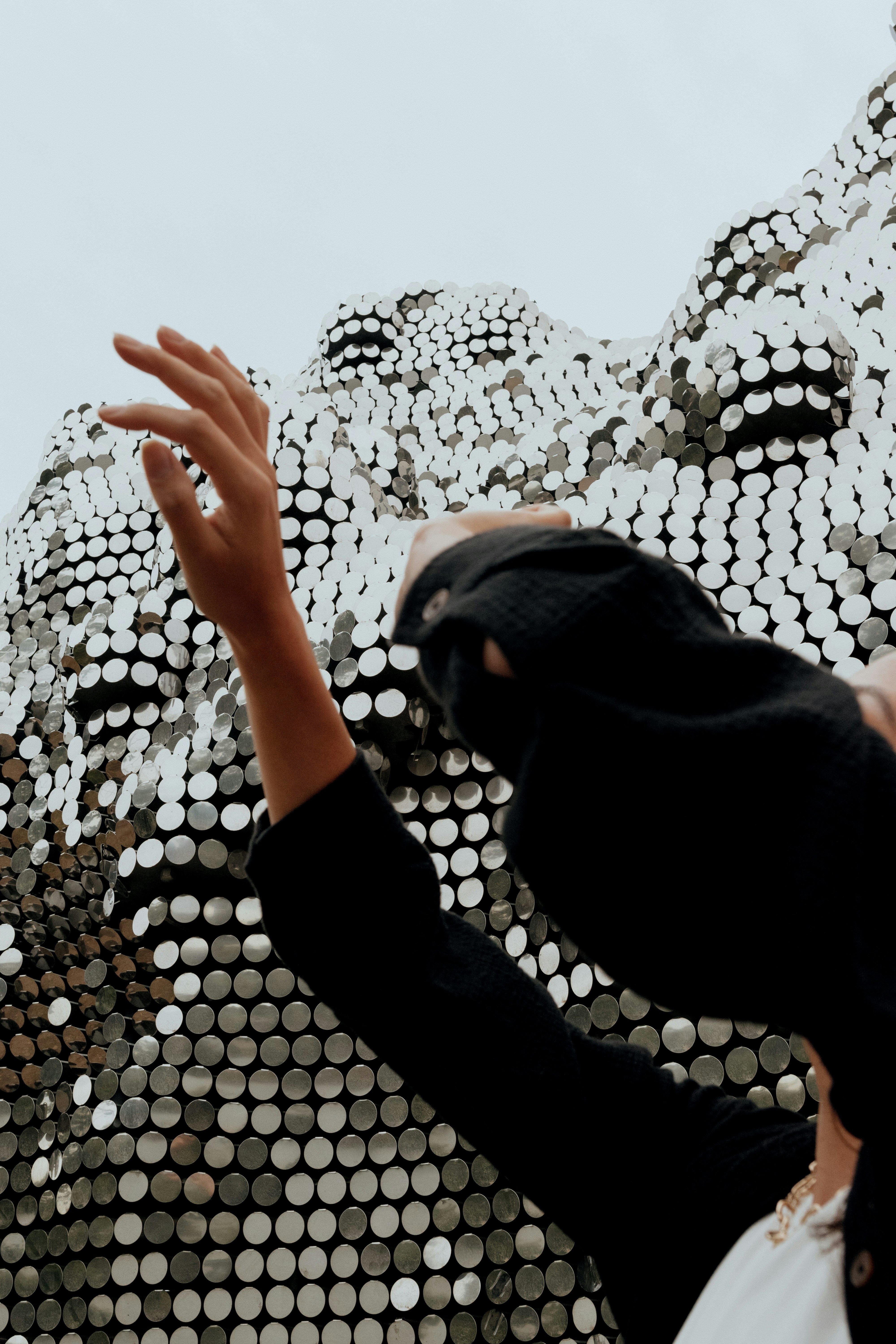 Raised Hands Against a Dotted Facade