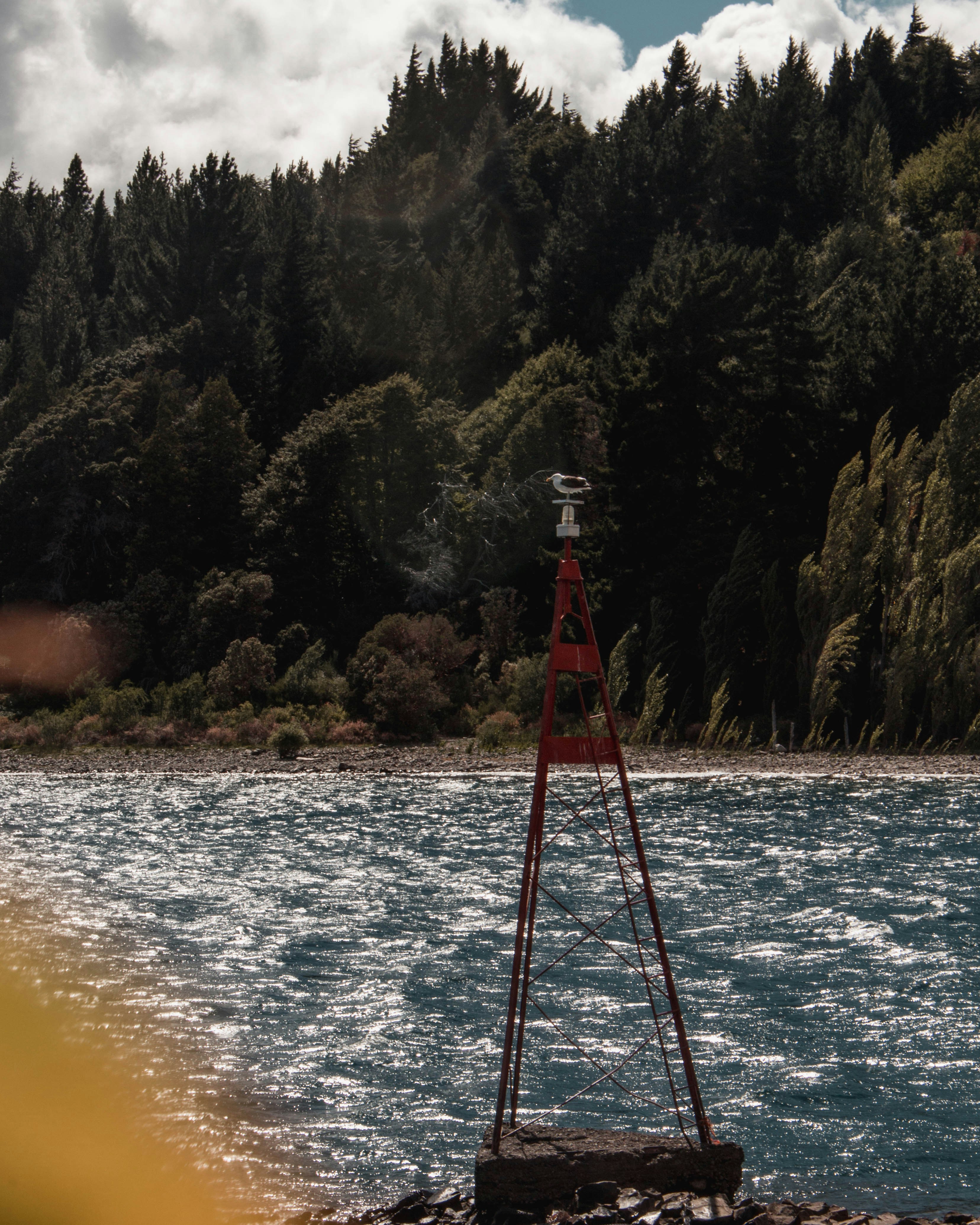 Red tripod beacon: a lone surveying pole rises above shimmering lake