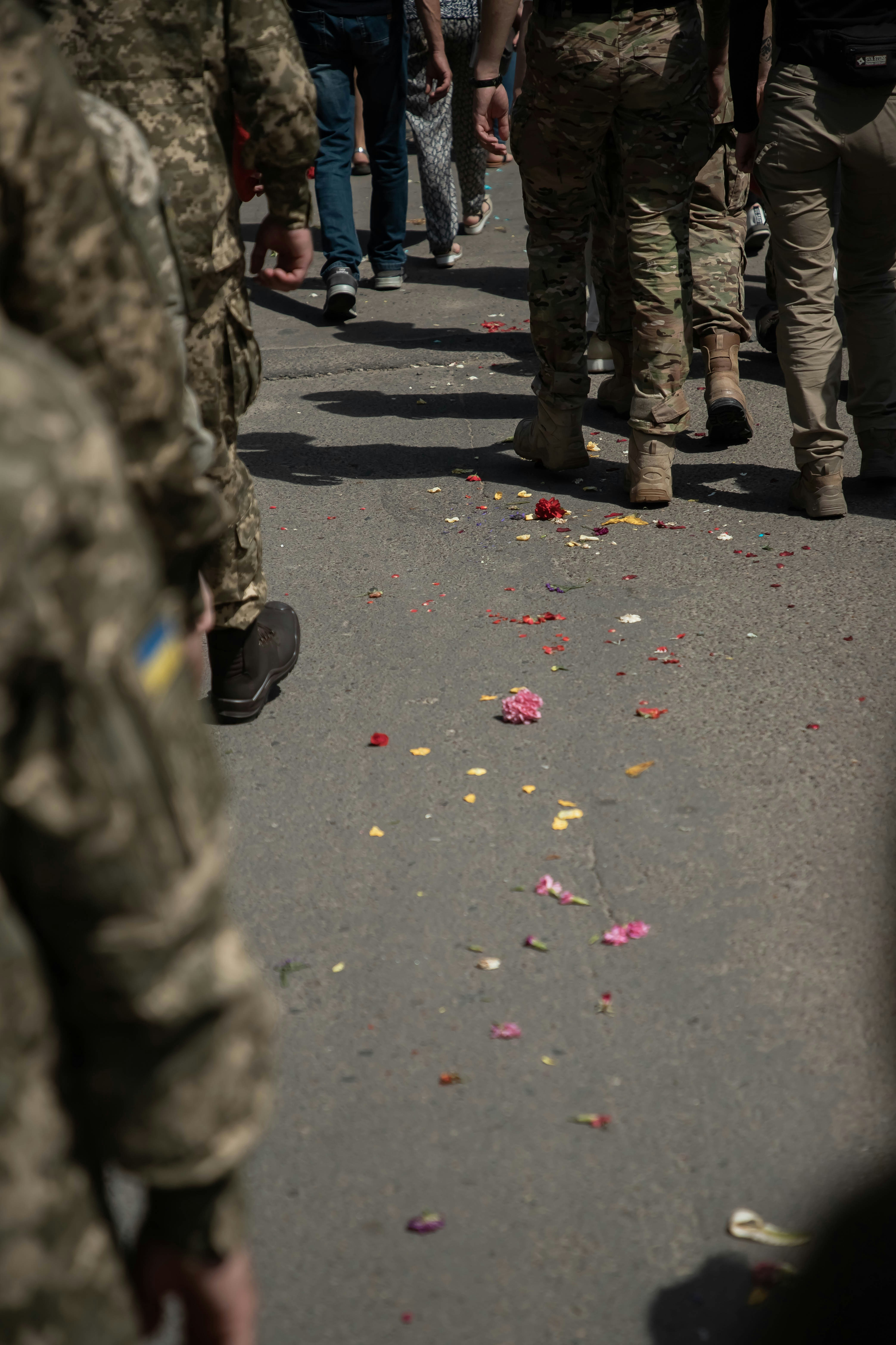 a group of people standing on a street with flowers on the ground