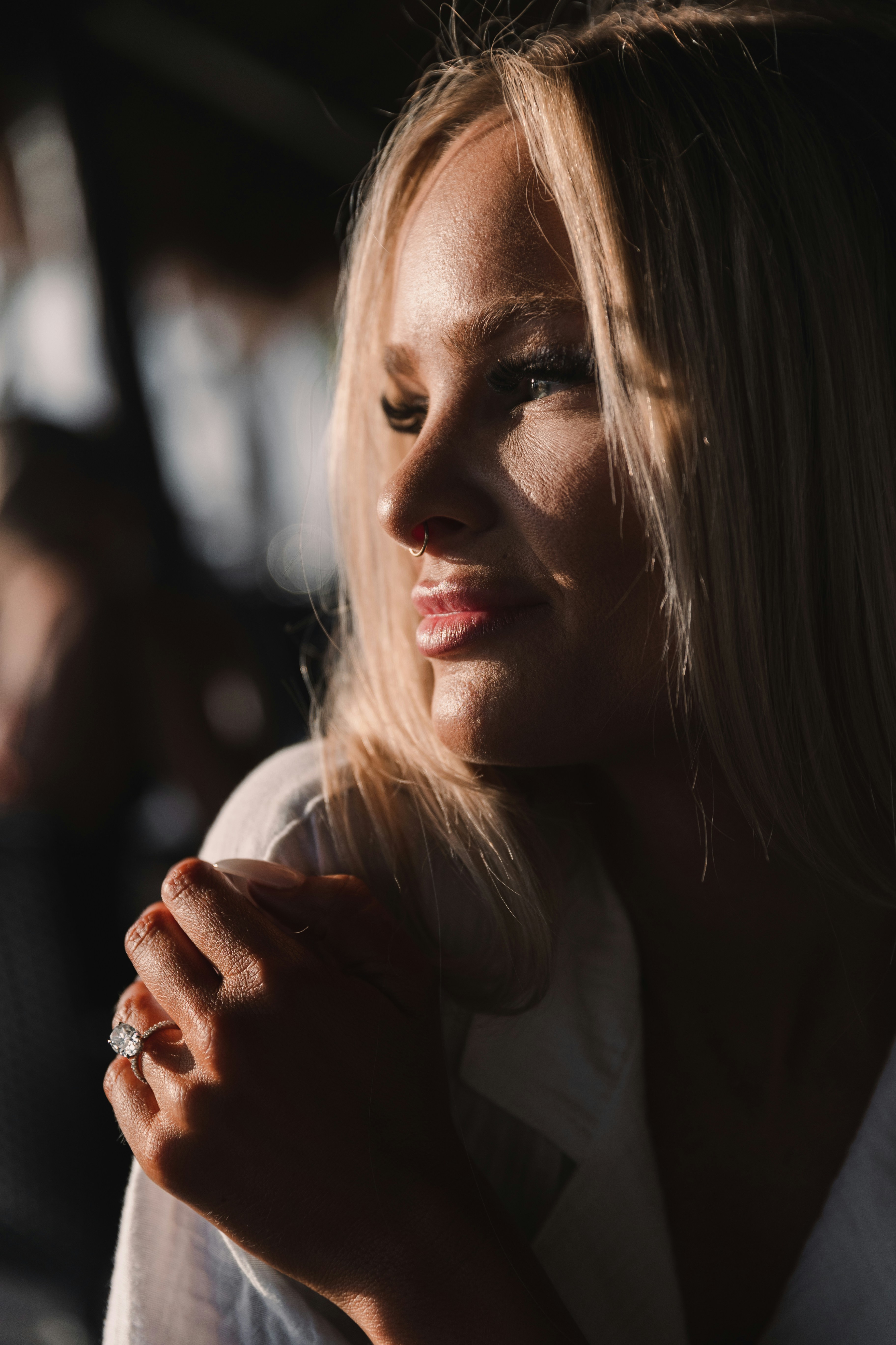 Woman gazing thoughtfully out of a window, her face softly illuminated by warm sunlight.