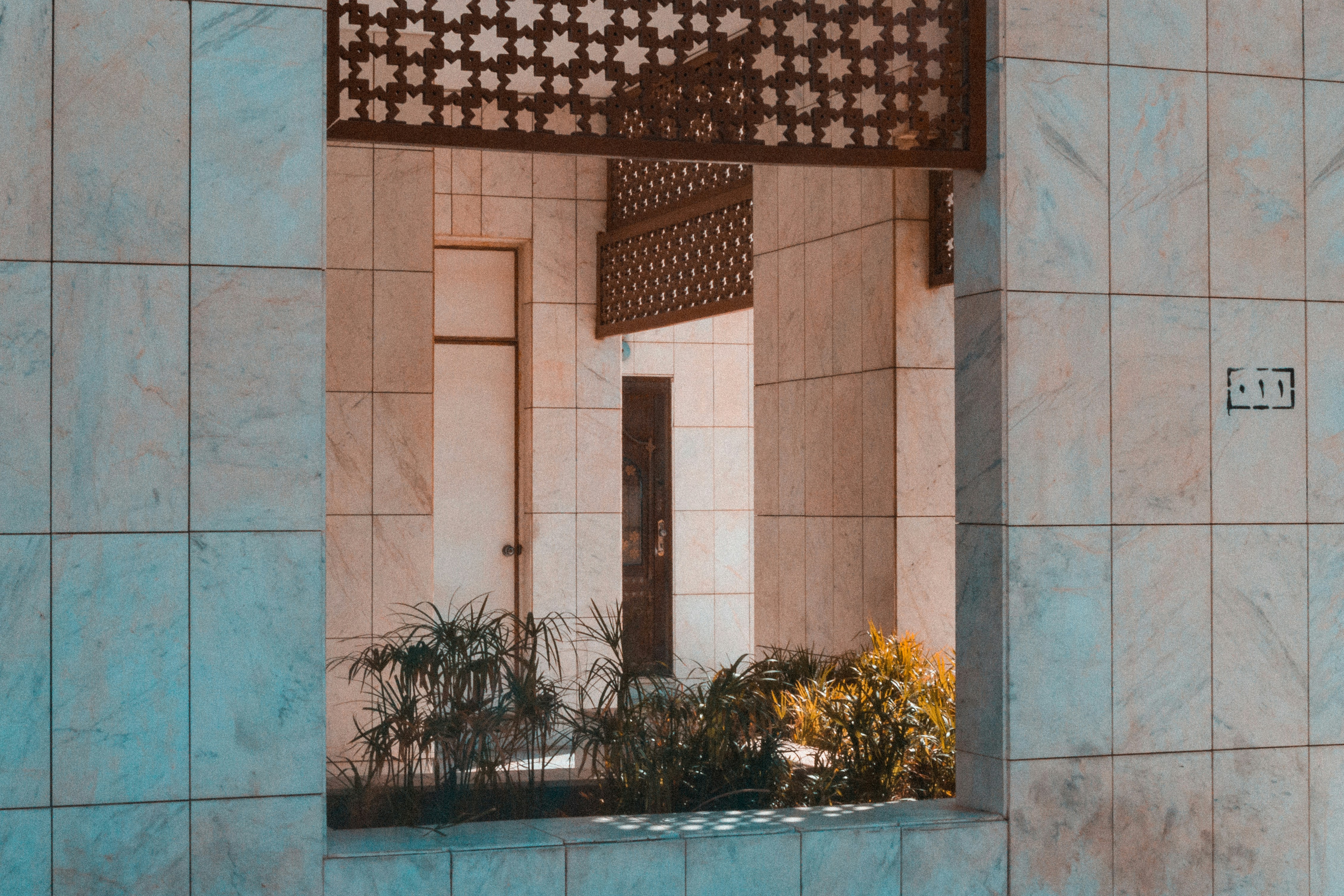 Intricate latticework frames a serene courtyard filled with lush greenery, showcasing a harmonious blend of architecture and nature.