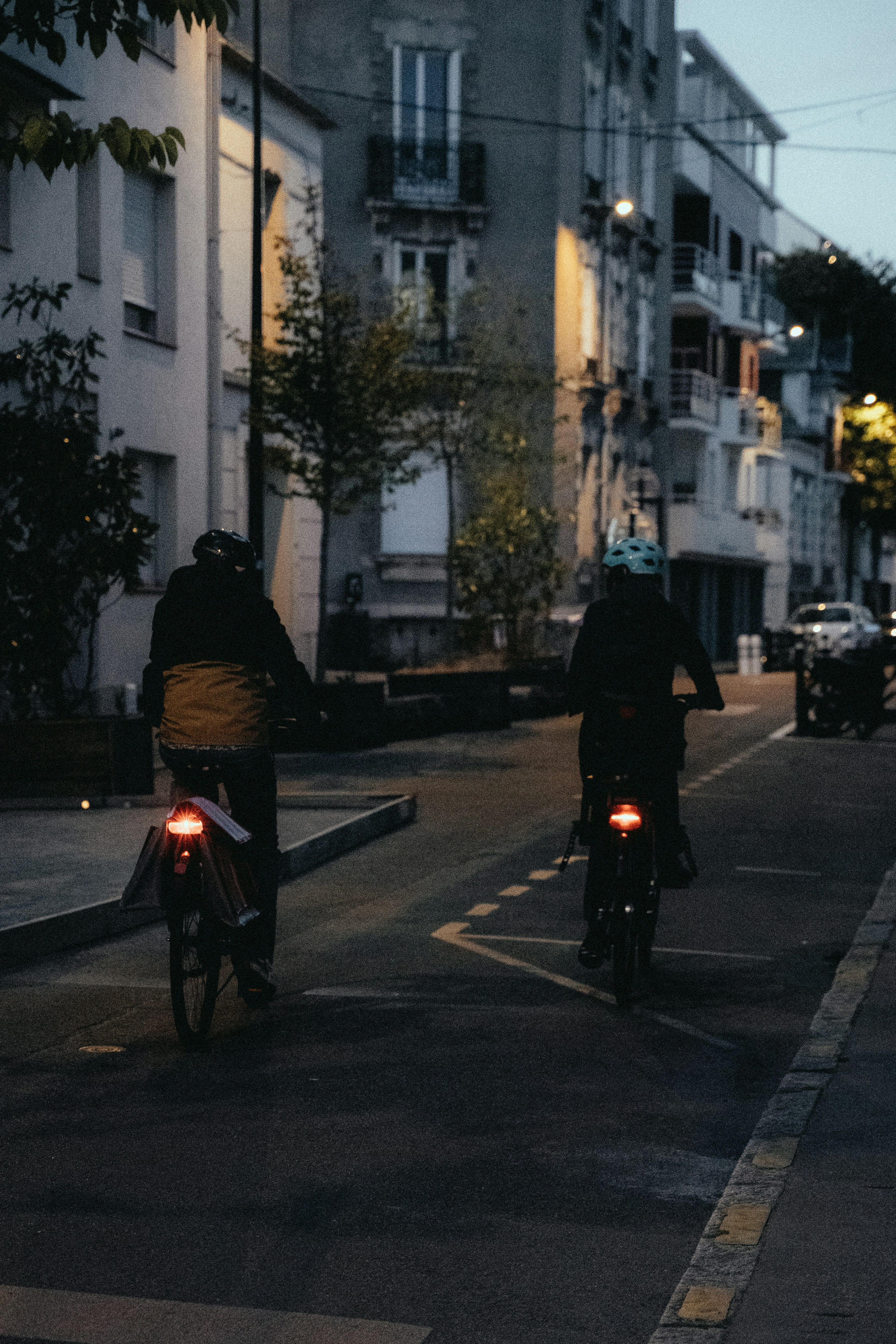 Two Cyclists Beneath Warm Street Lights on a Quiet City Street