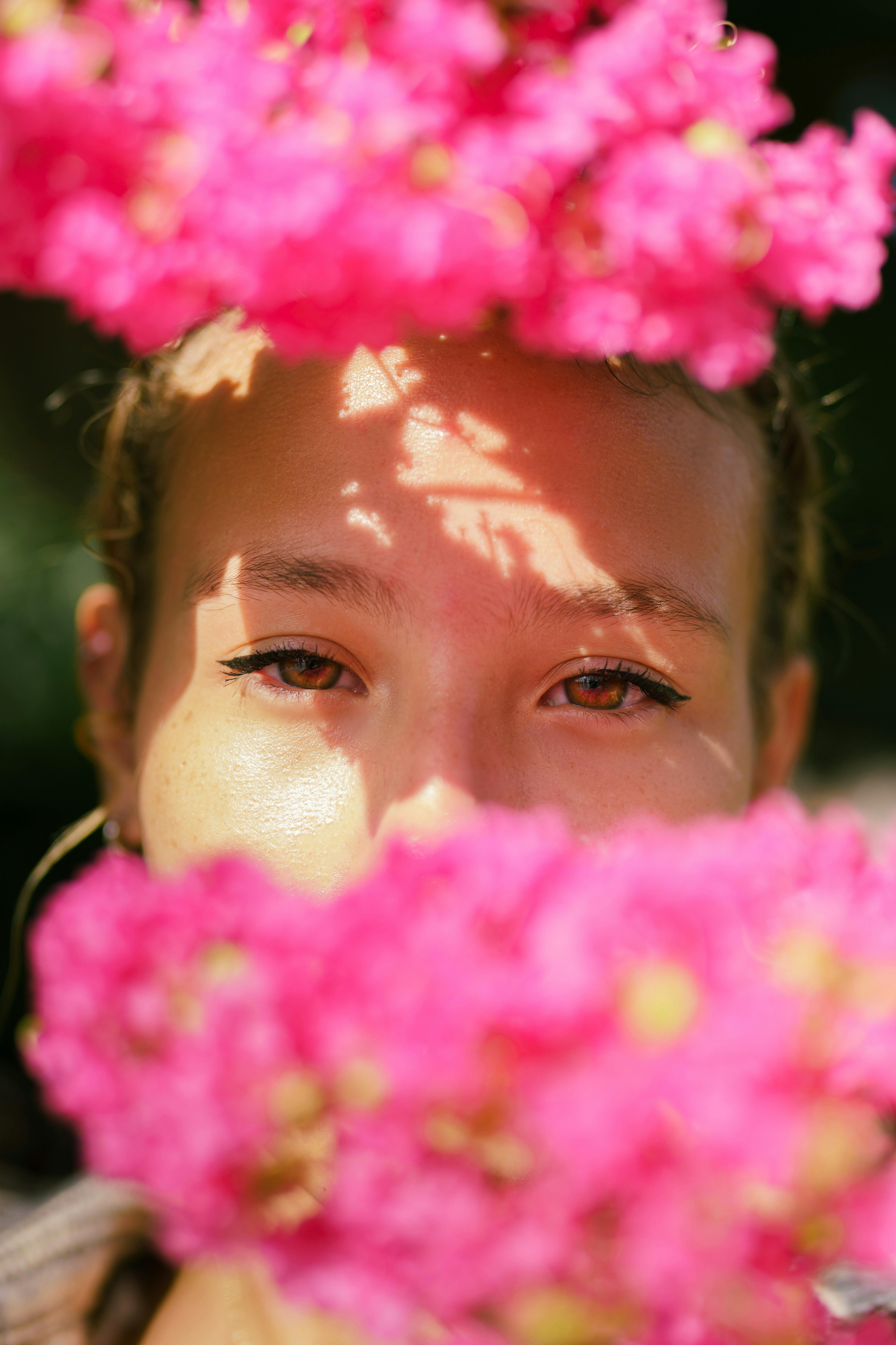 Glimmer Through a Pink Veil: A Sunlit Portrait Framed by Fuchsia Blooms