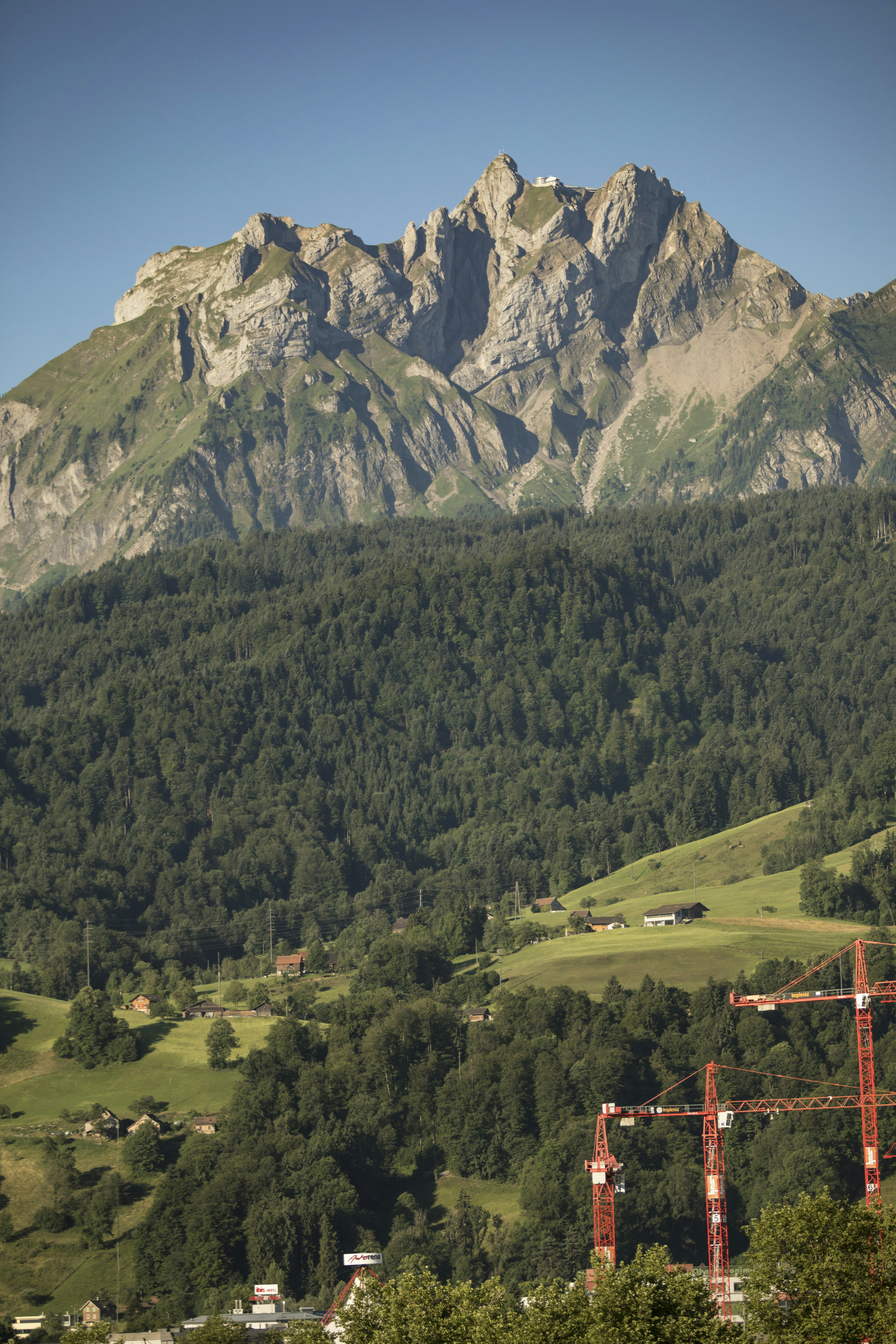 Foto zum Thema Ein großer Berg mit Bäumen und einer Straße darunter ...