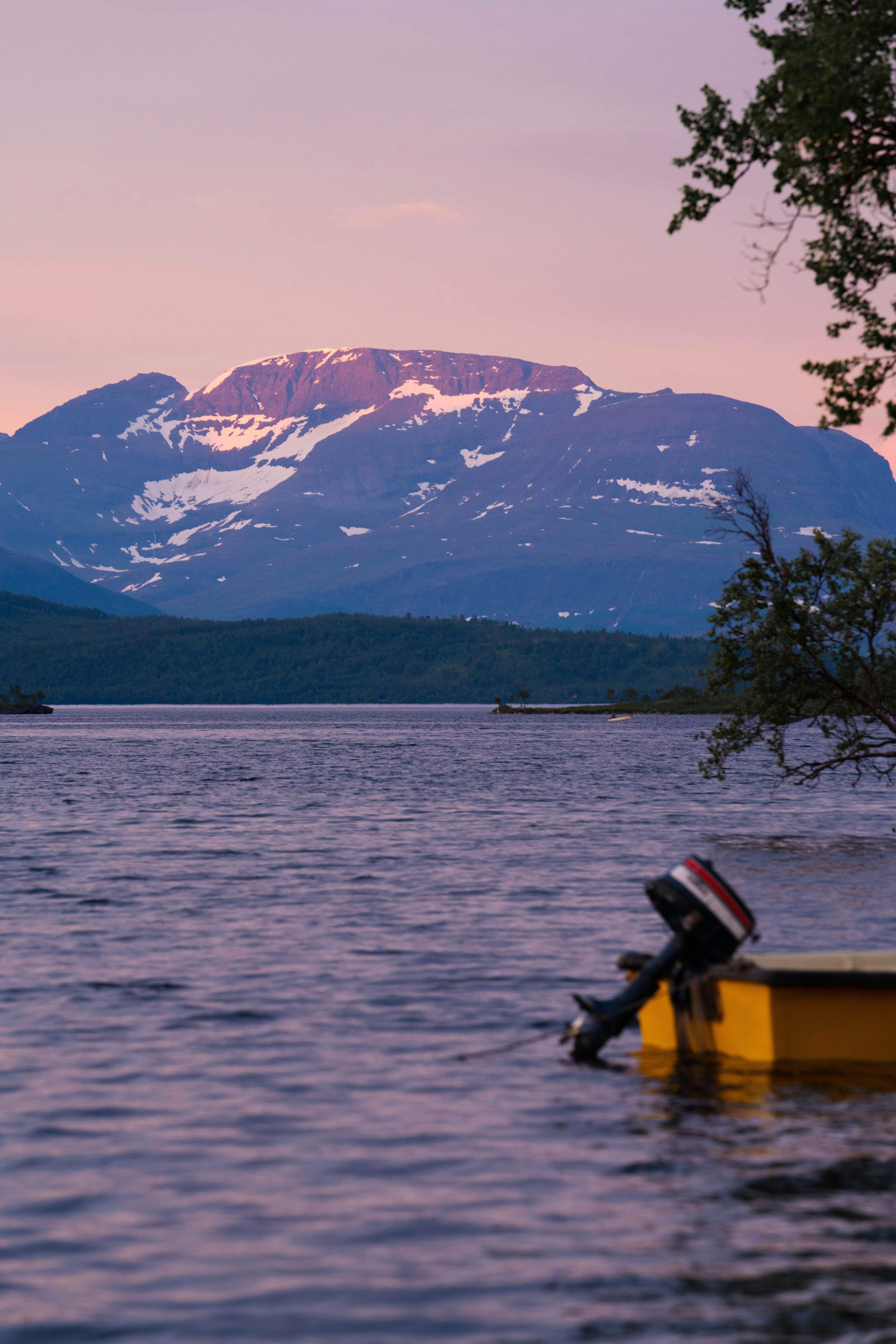 Twilight Mountain over Tranquil Waters with a Vibrant Powerboat Vanished in the Corner