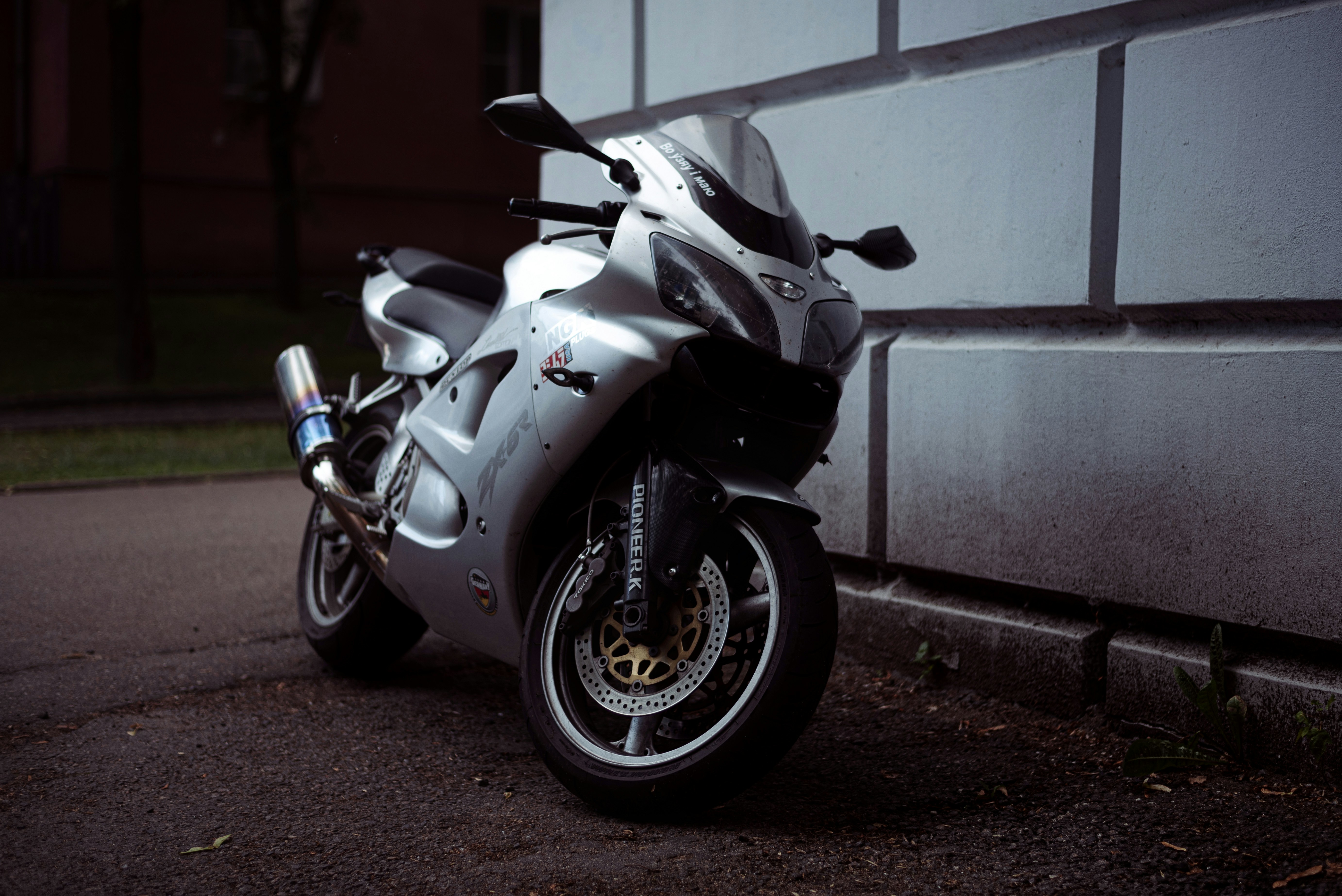 Shaded Silver Racer: A Sportbike Tucked Against the Wall at Dusk