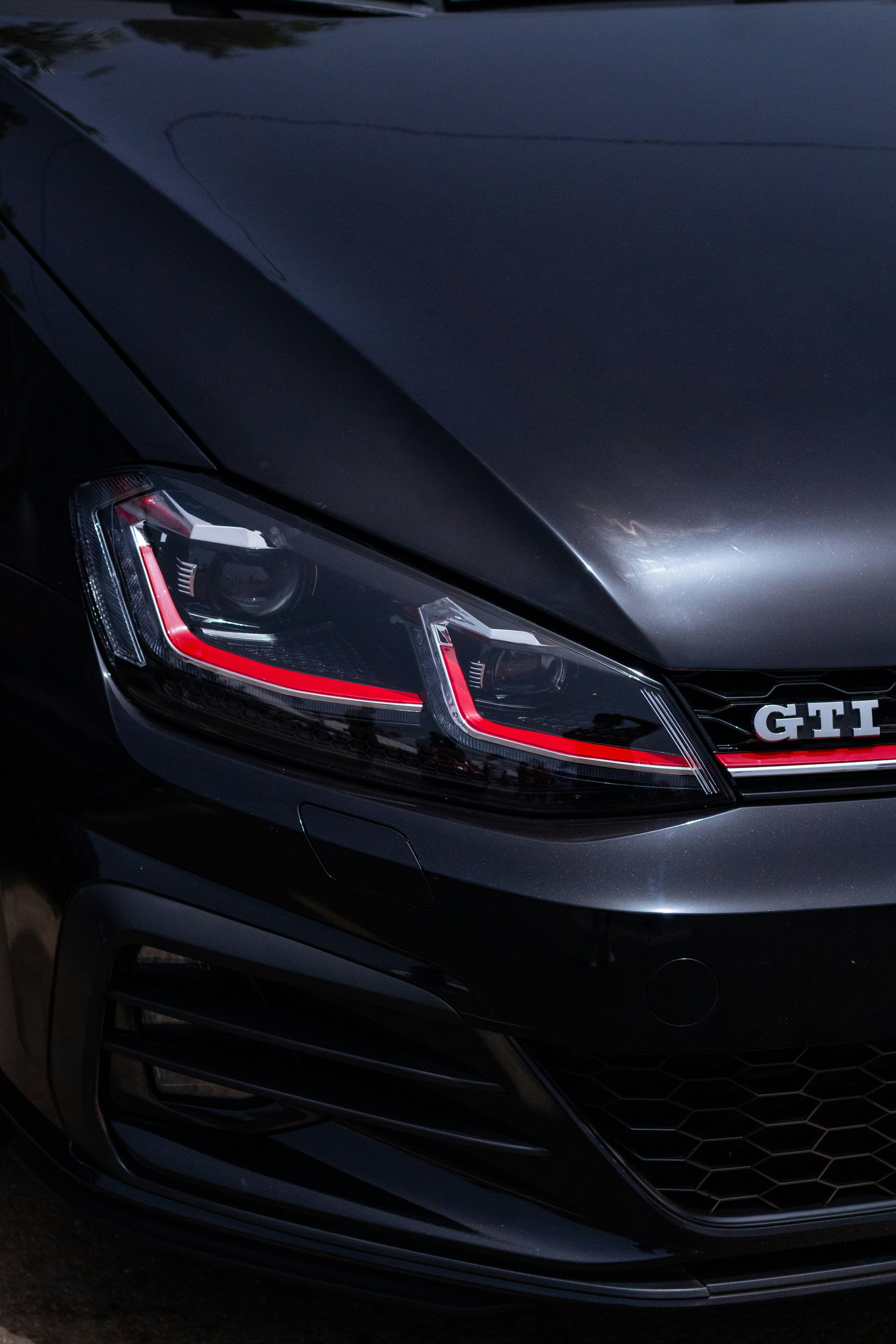 Close-up of a sleek black GTI front end showcasing its distinctive headlights and emblem.